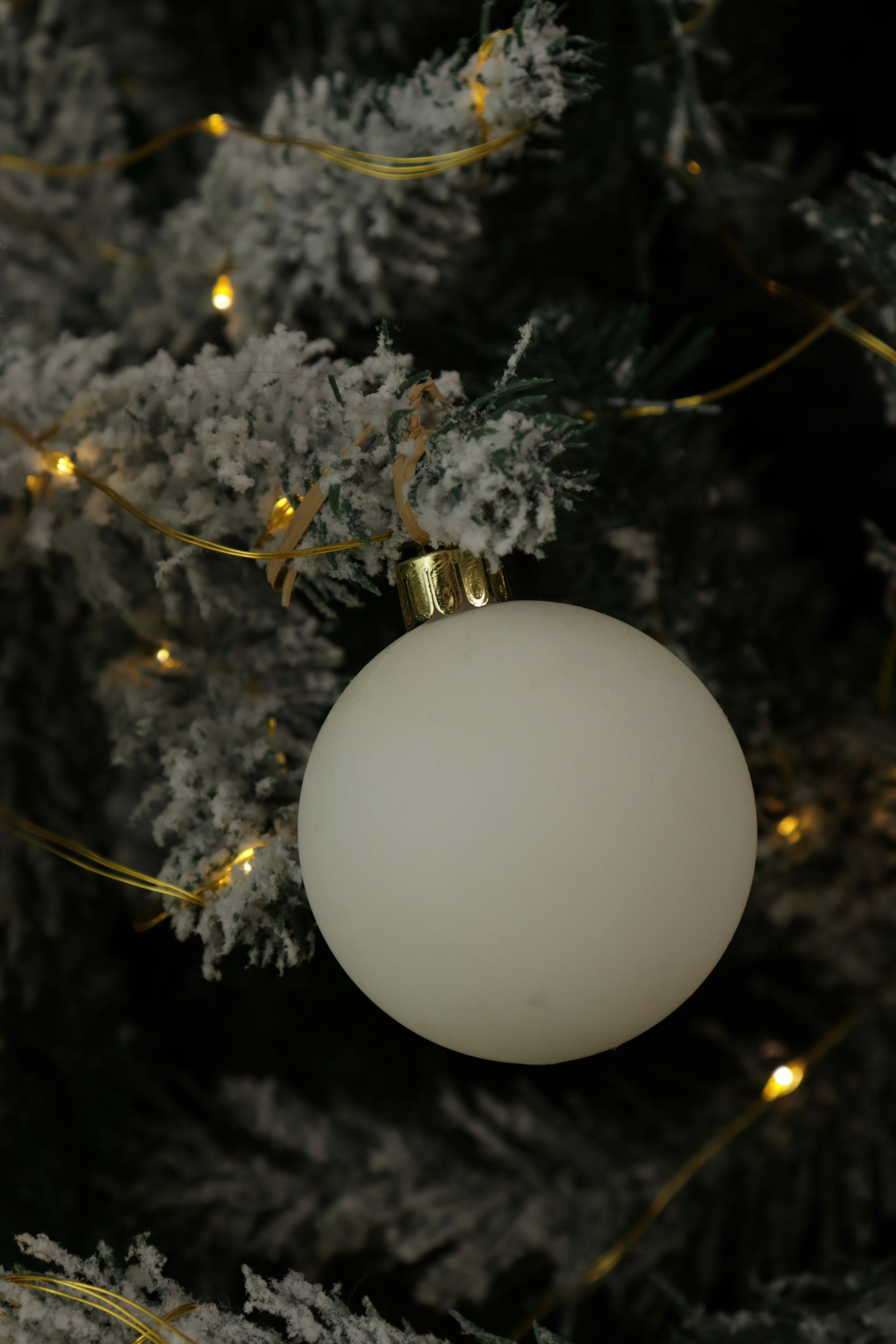 Glowing Christmas Ornament Nestled in Snow-dusted Fir