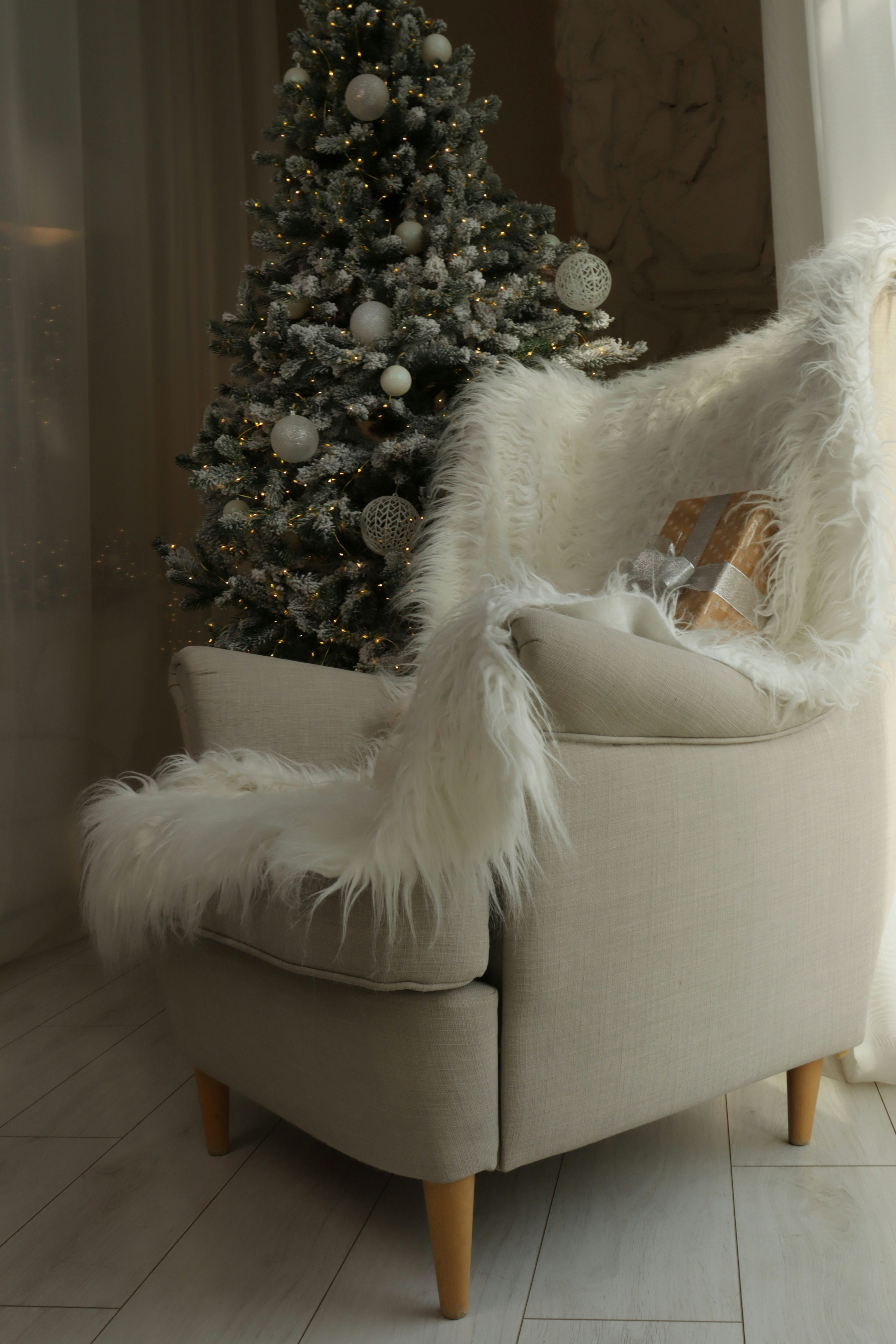 Cozy Winter Corner: Plush Chair Beside a Festive, Sparkling Christmas Tree