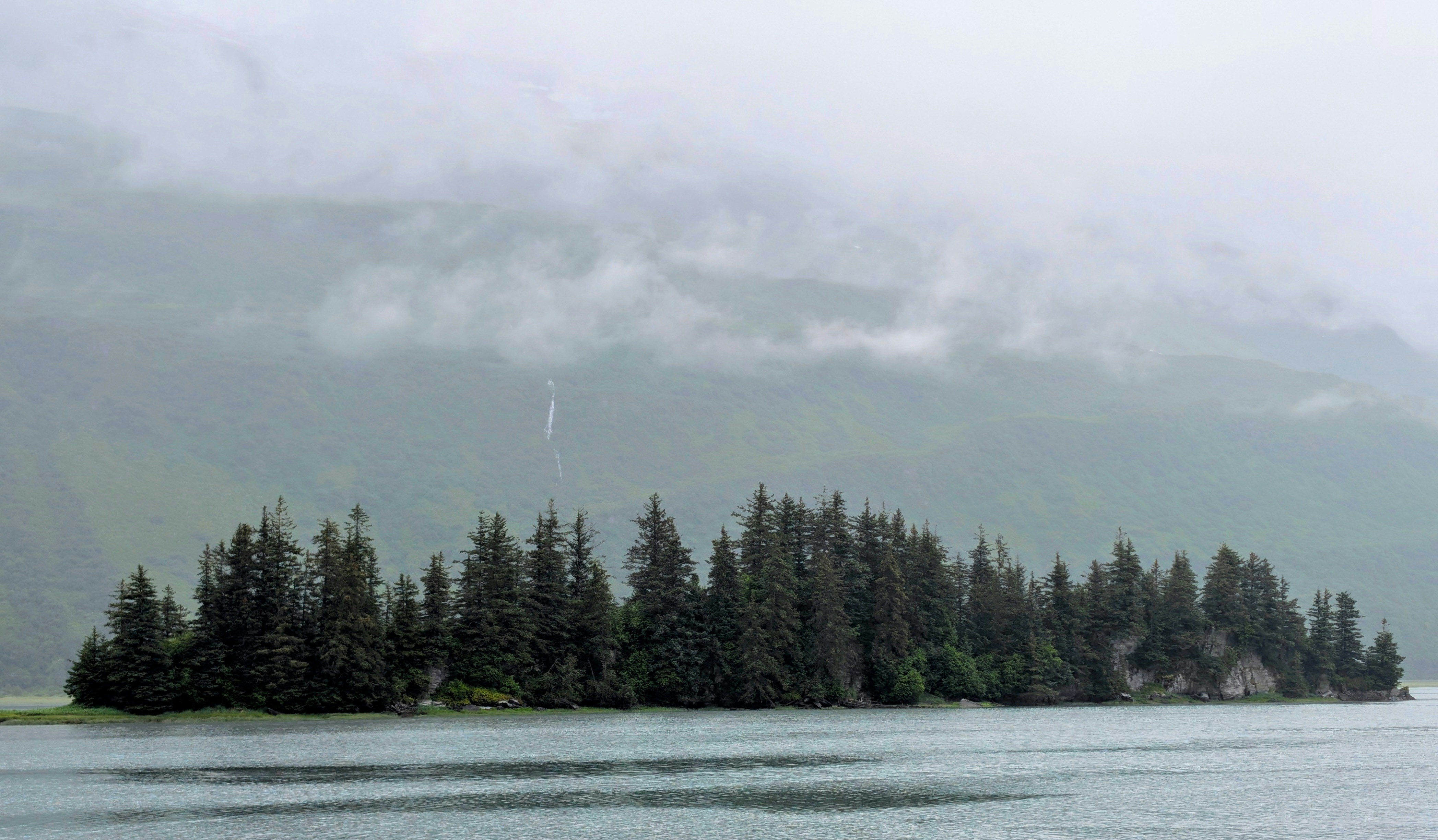 Mist-Lined Island Ridge Emerging from Quiet Fjord