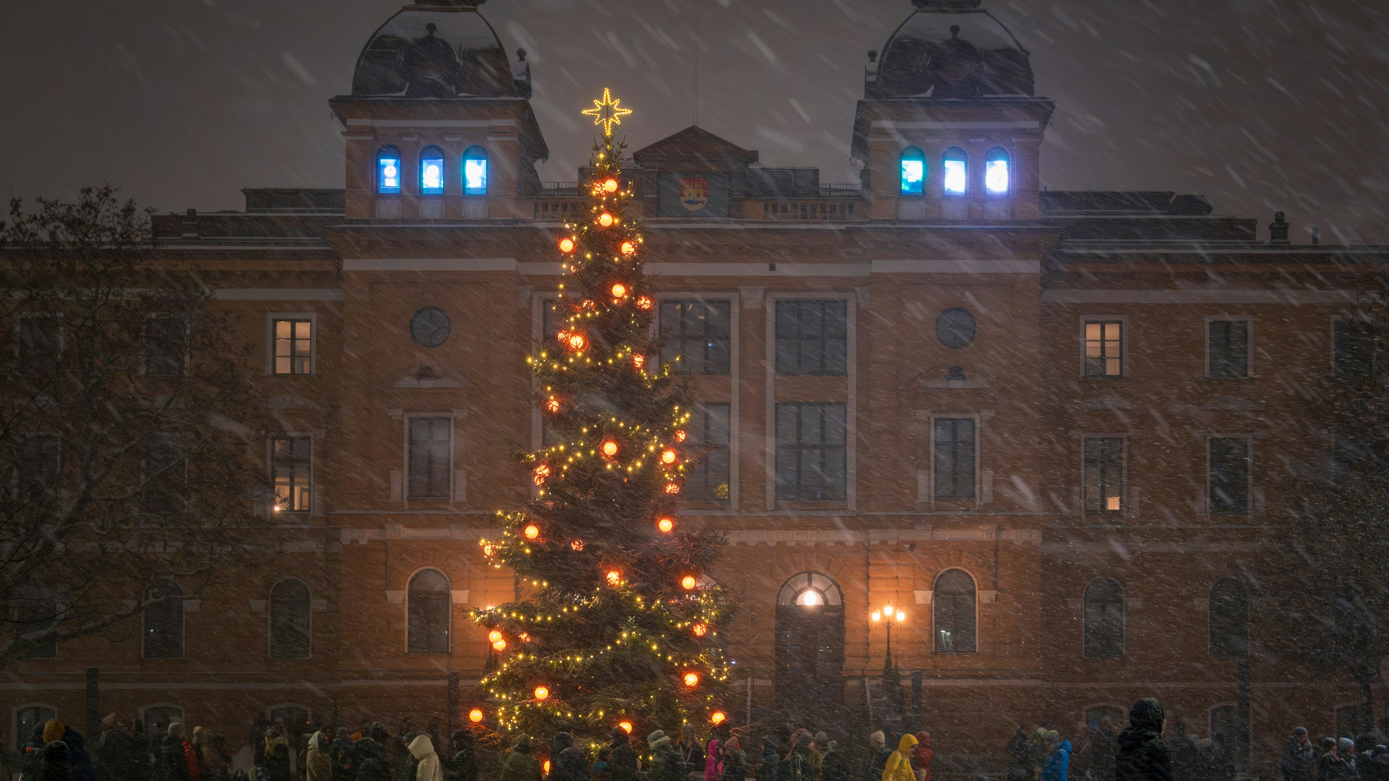 Christmas tree in front of building during snowfall photo – Free Snow ...