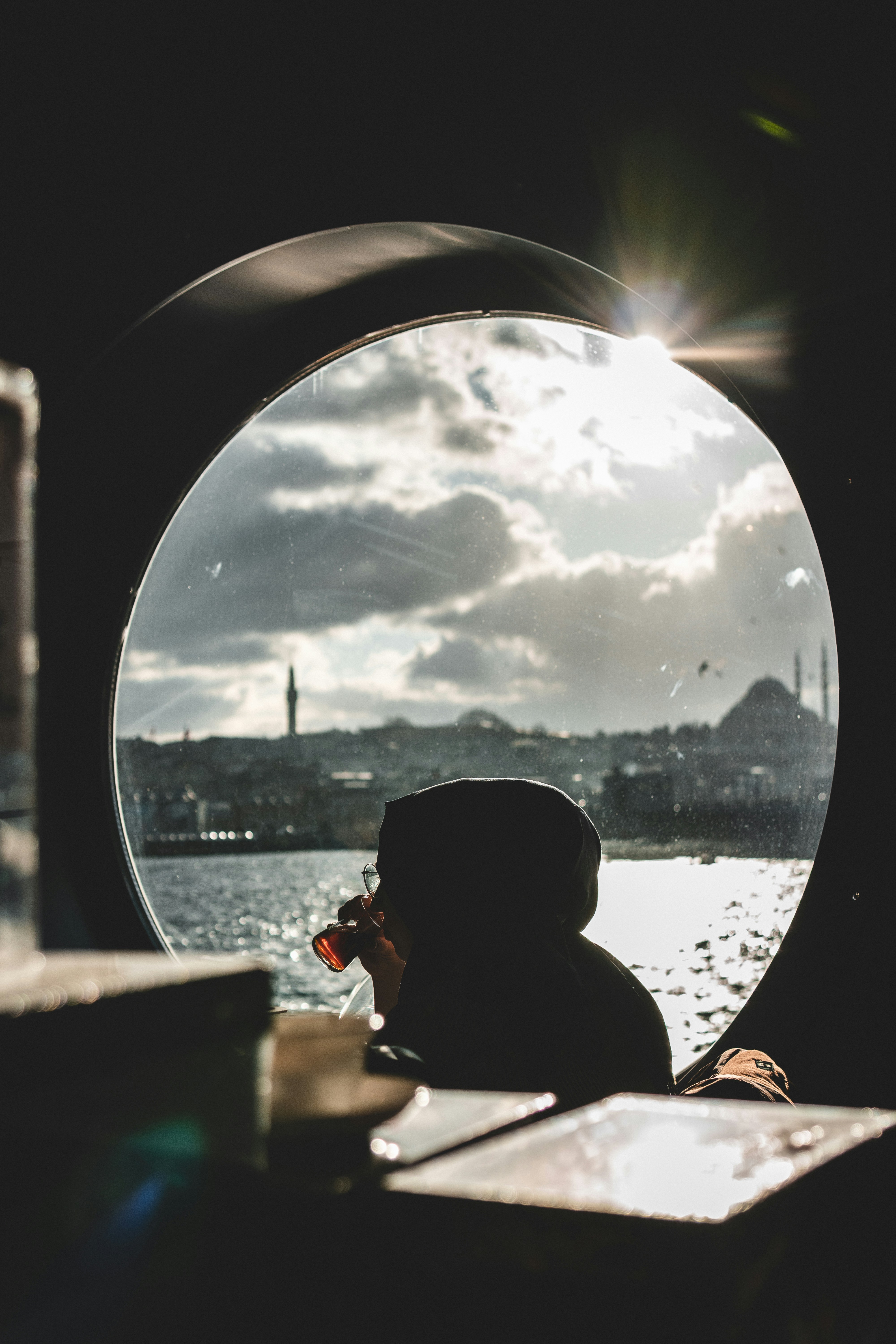 Silhouette at the Circular Window: Quiet Moment Against the Harbour Light