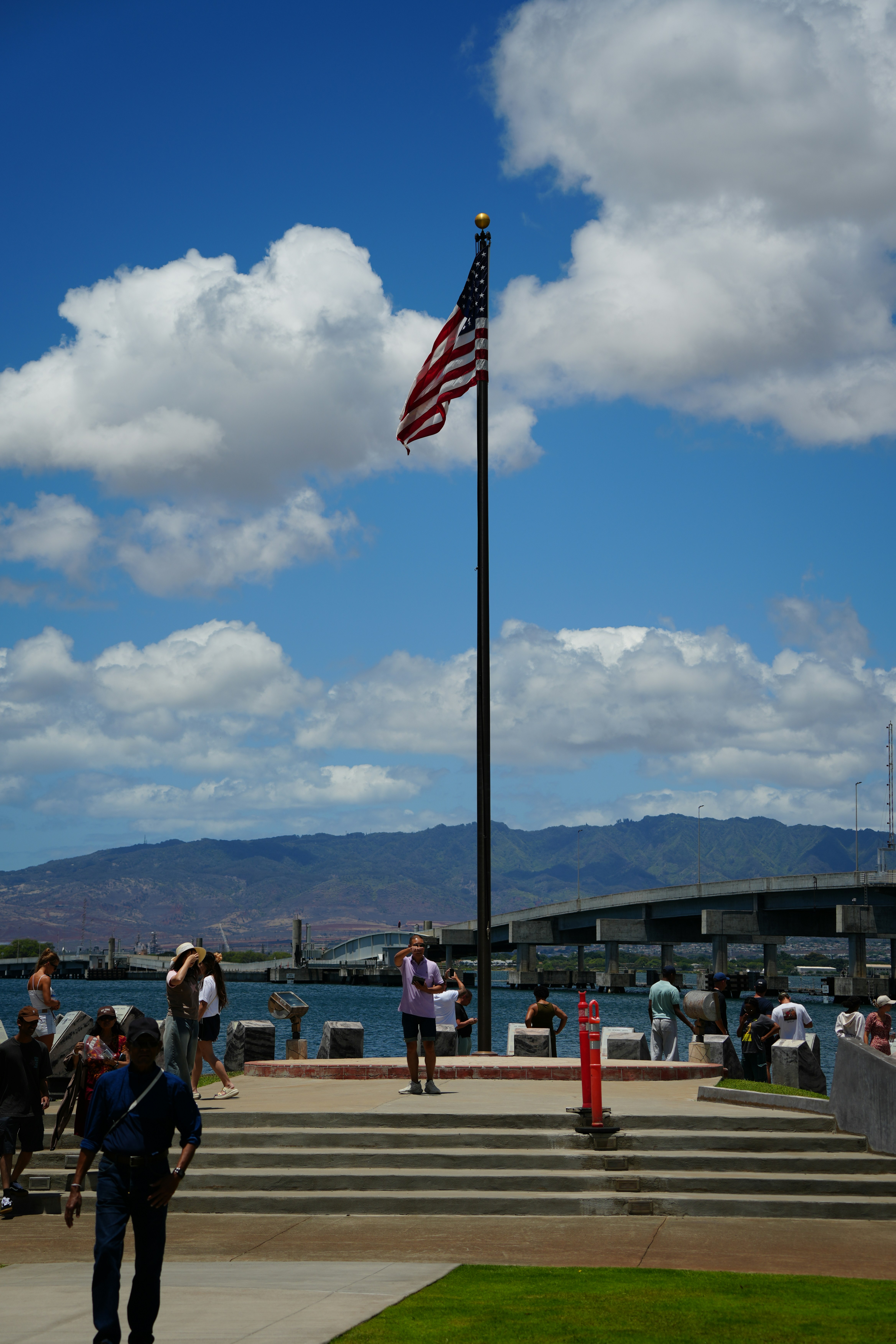 Flagpole in a sunlit harbor plaza beneath a blue sky