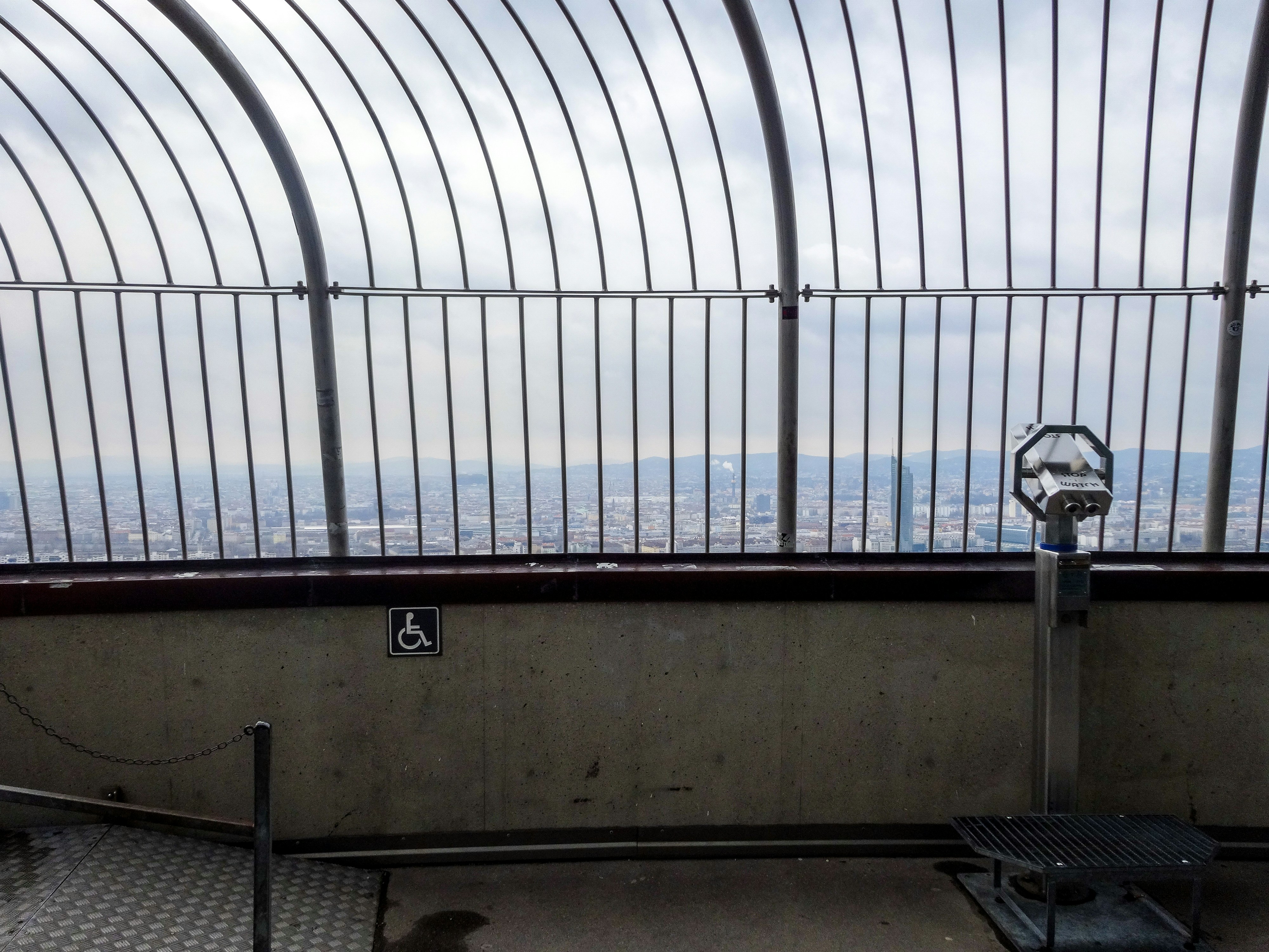 Ridge View Overlook: Curved Metal Grille Framing a Distant Cityscape