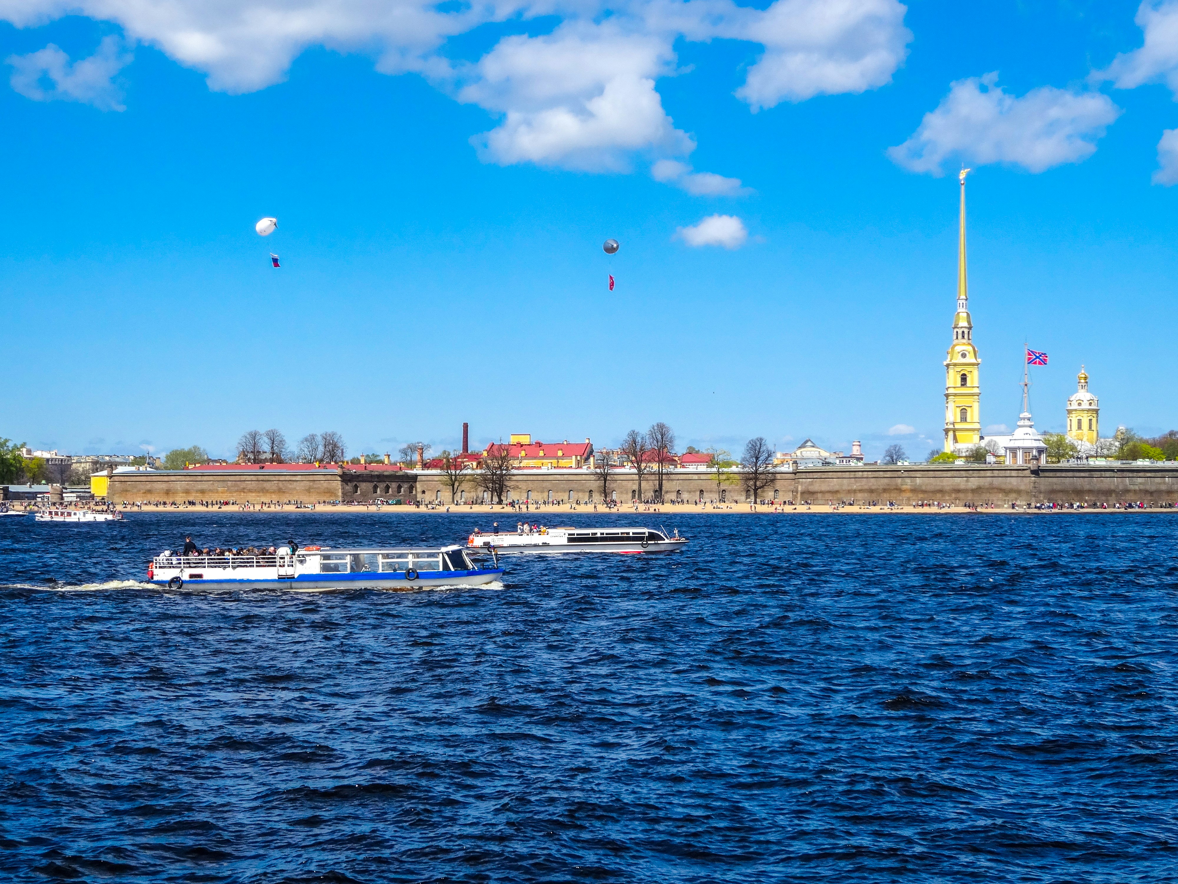 Riverine Parade: Boats Skim the Baltic Azure Past a Historic Waterfront