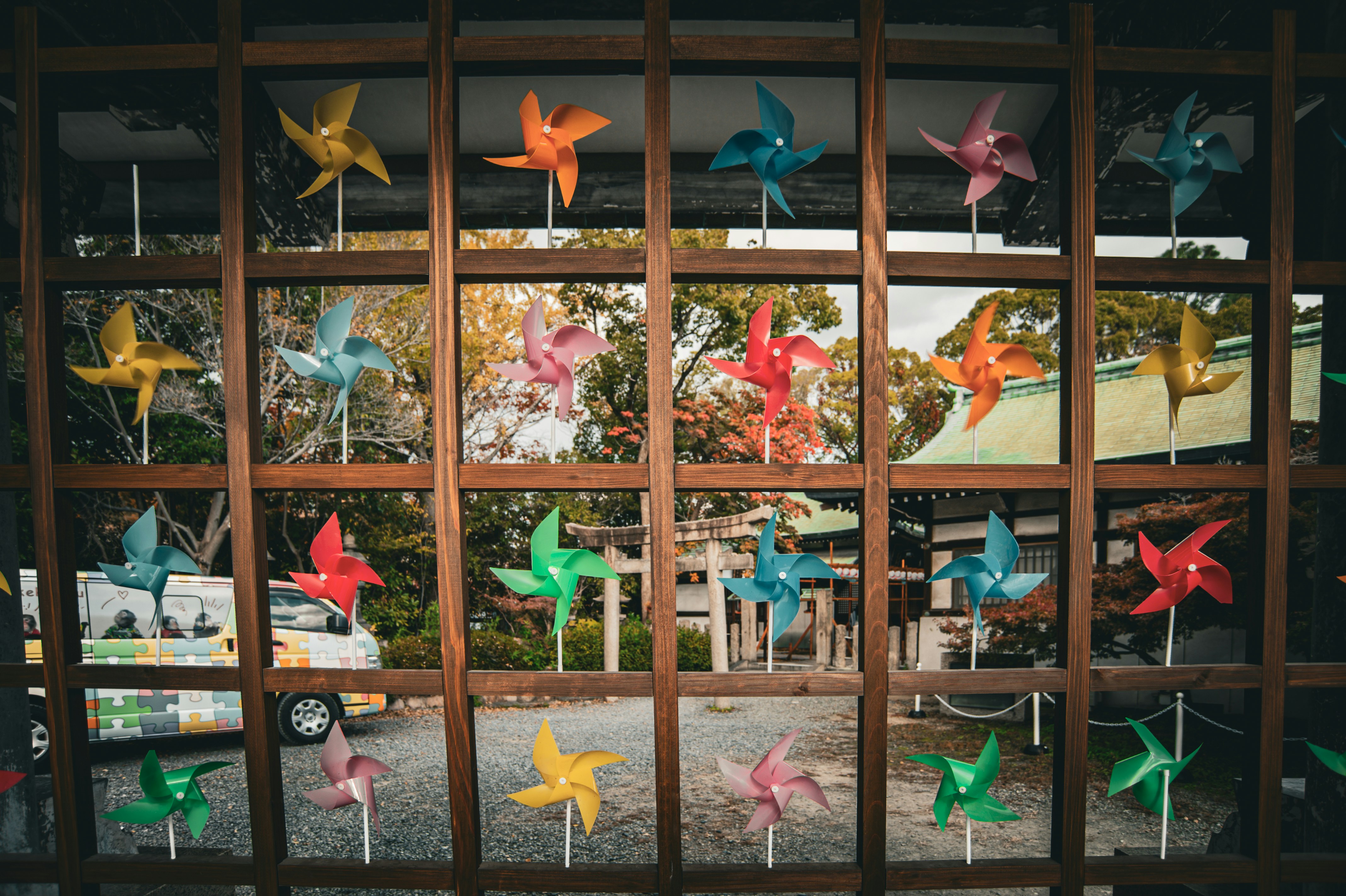 Colorful windmills behind grid: a framed window of motion