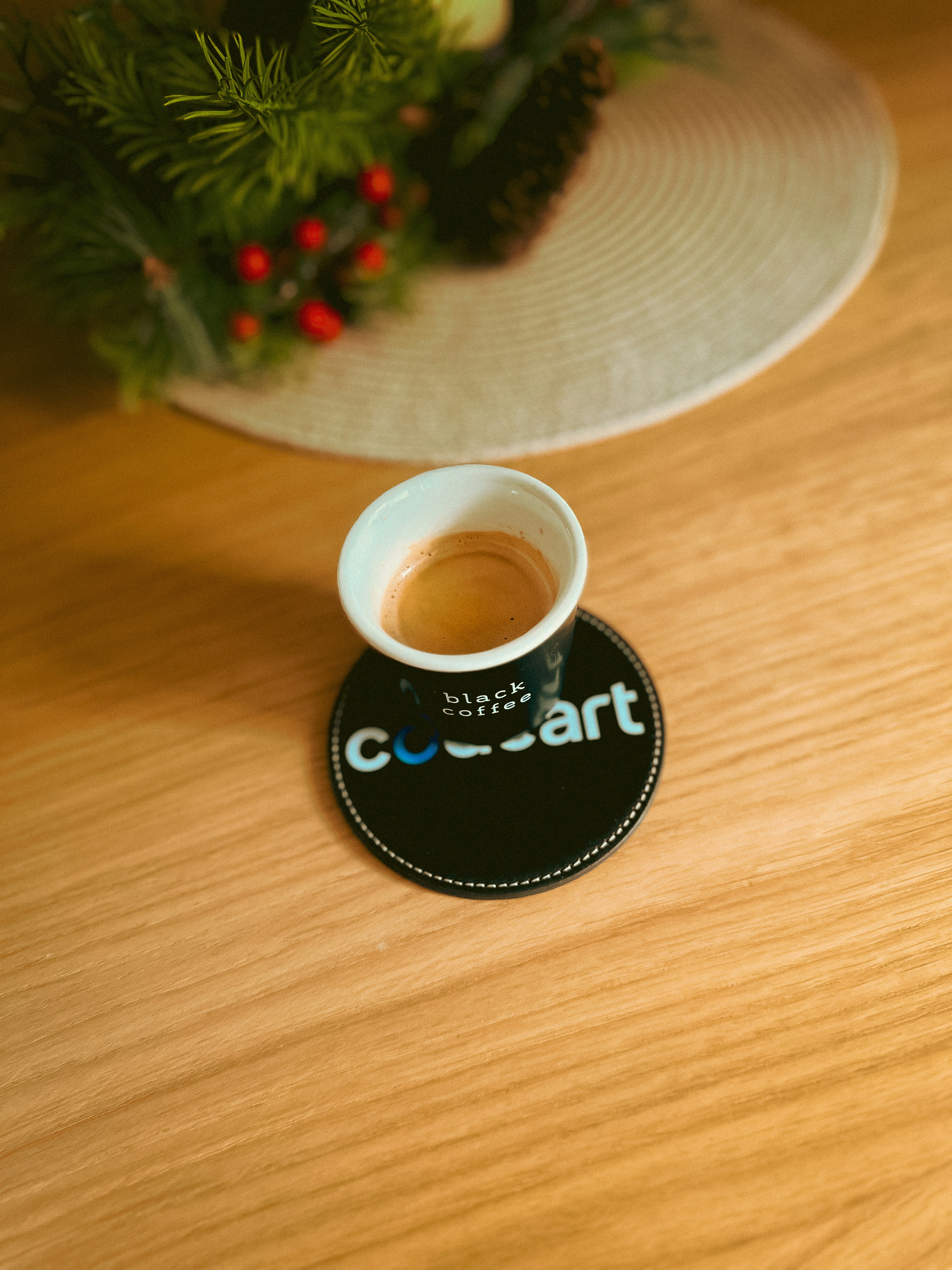 A close-up shot of a mini coffee cup on a wooden surface, captured with shallow depth of field and warm tones.