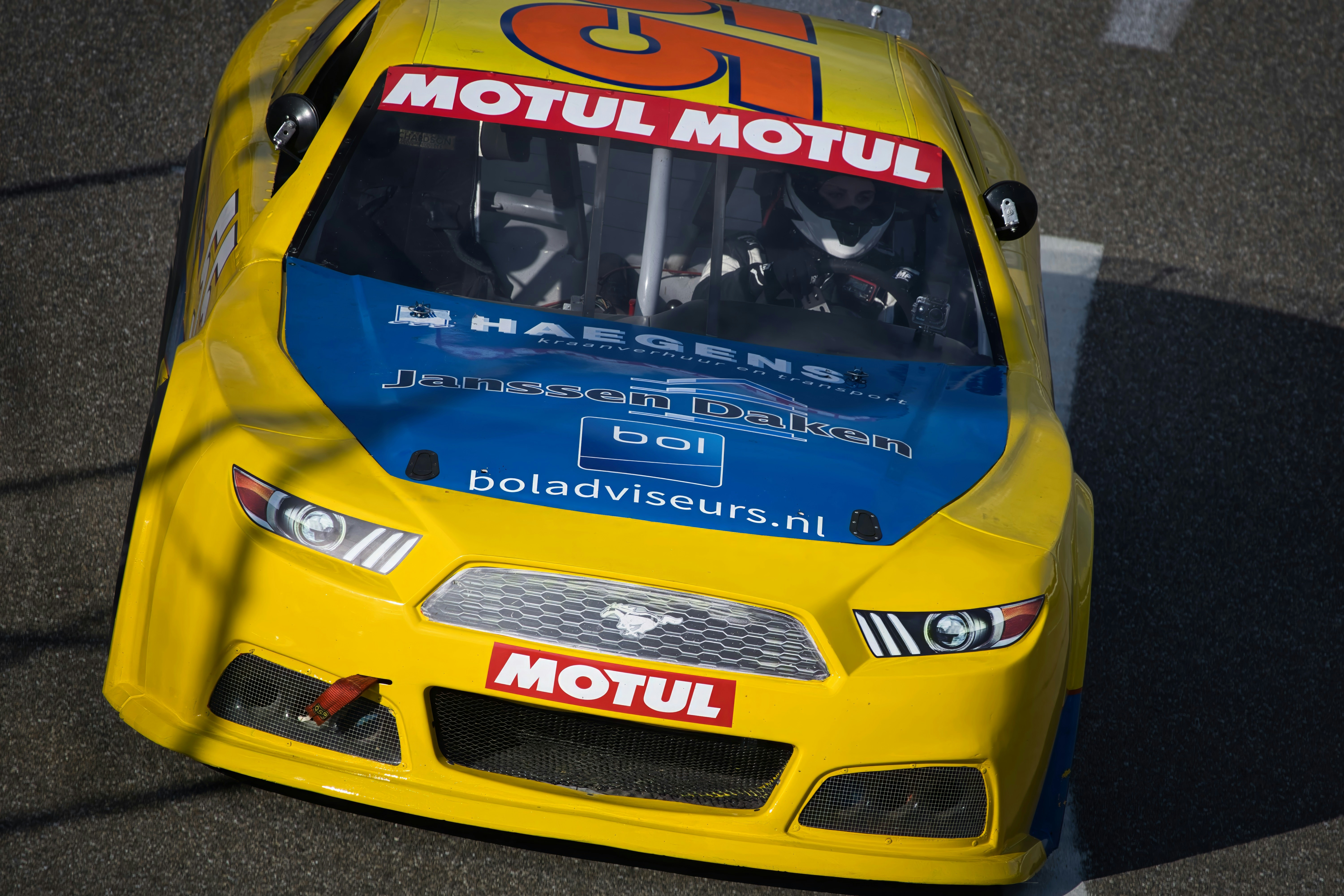 Yellow race car pausing mid-track: a high-speed front view with sponsor branding