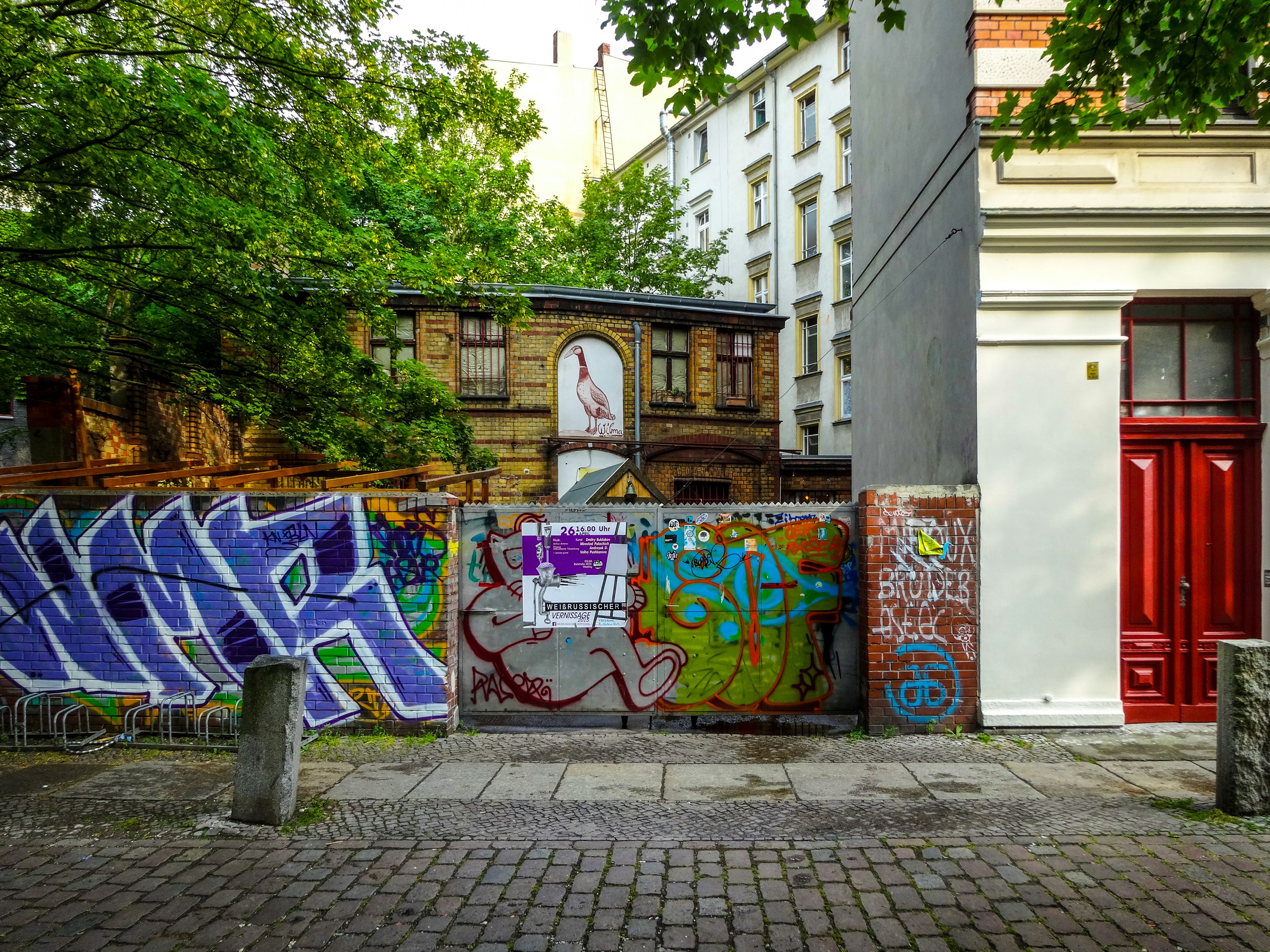 Graffiti-covered wall with red door and buildings