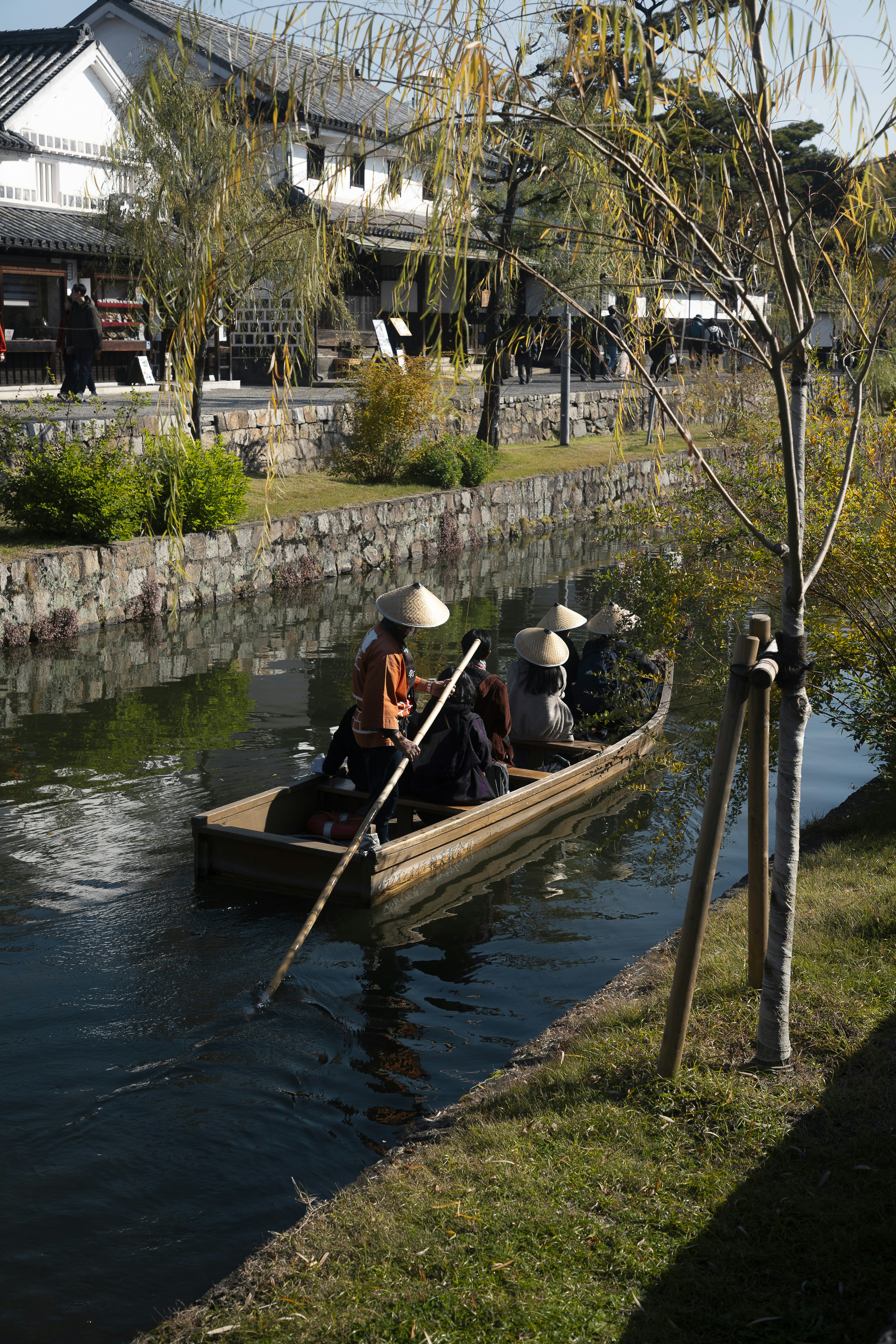 Rowers in a tranquil canal beneath a traditional riverside arcade