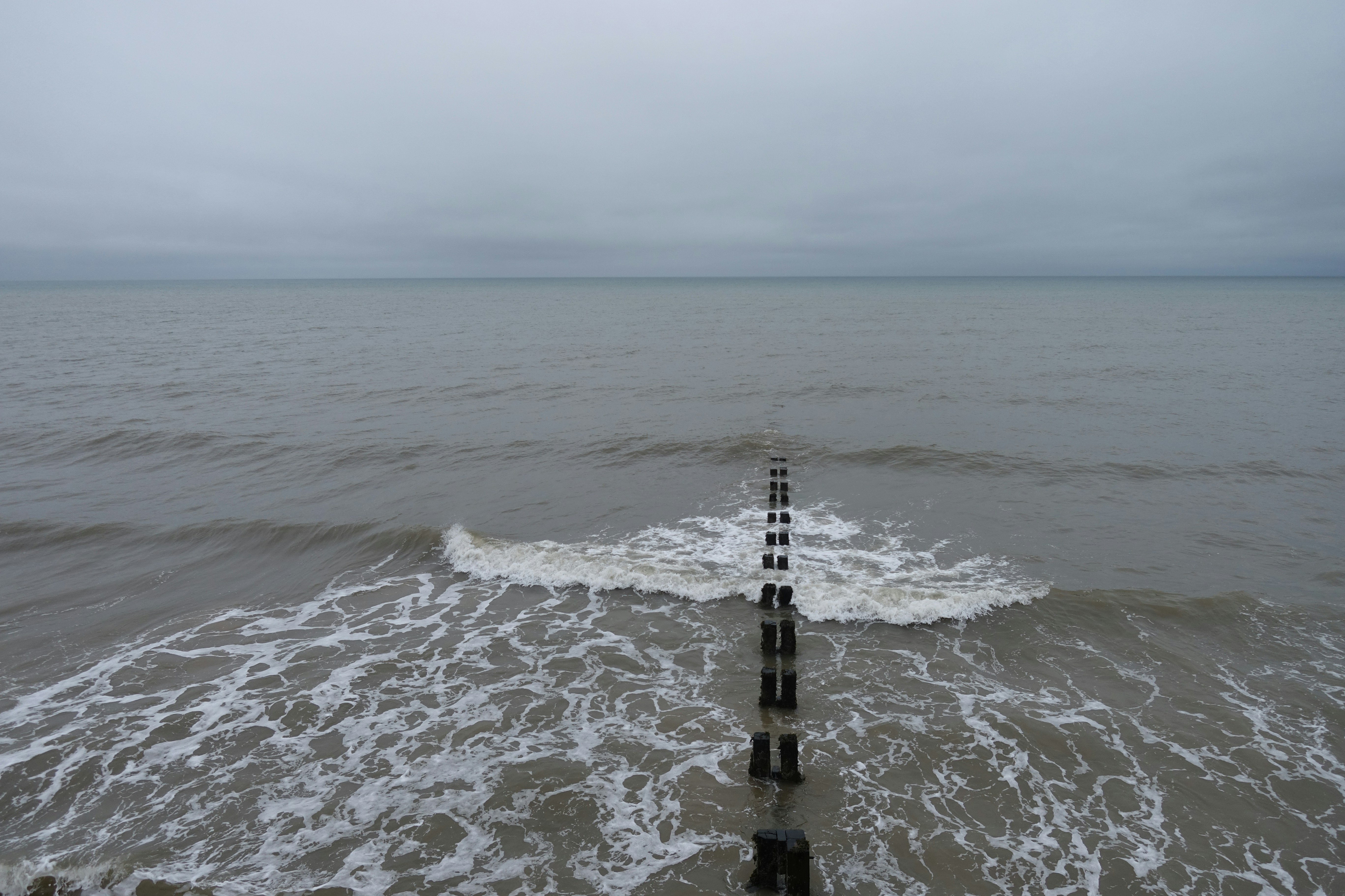 Promenade of Waves: A Quiet Breakwater under a Leaden Sky