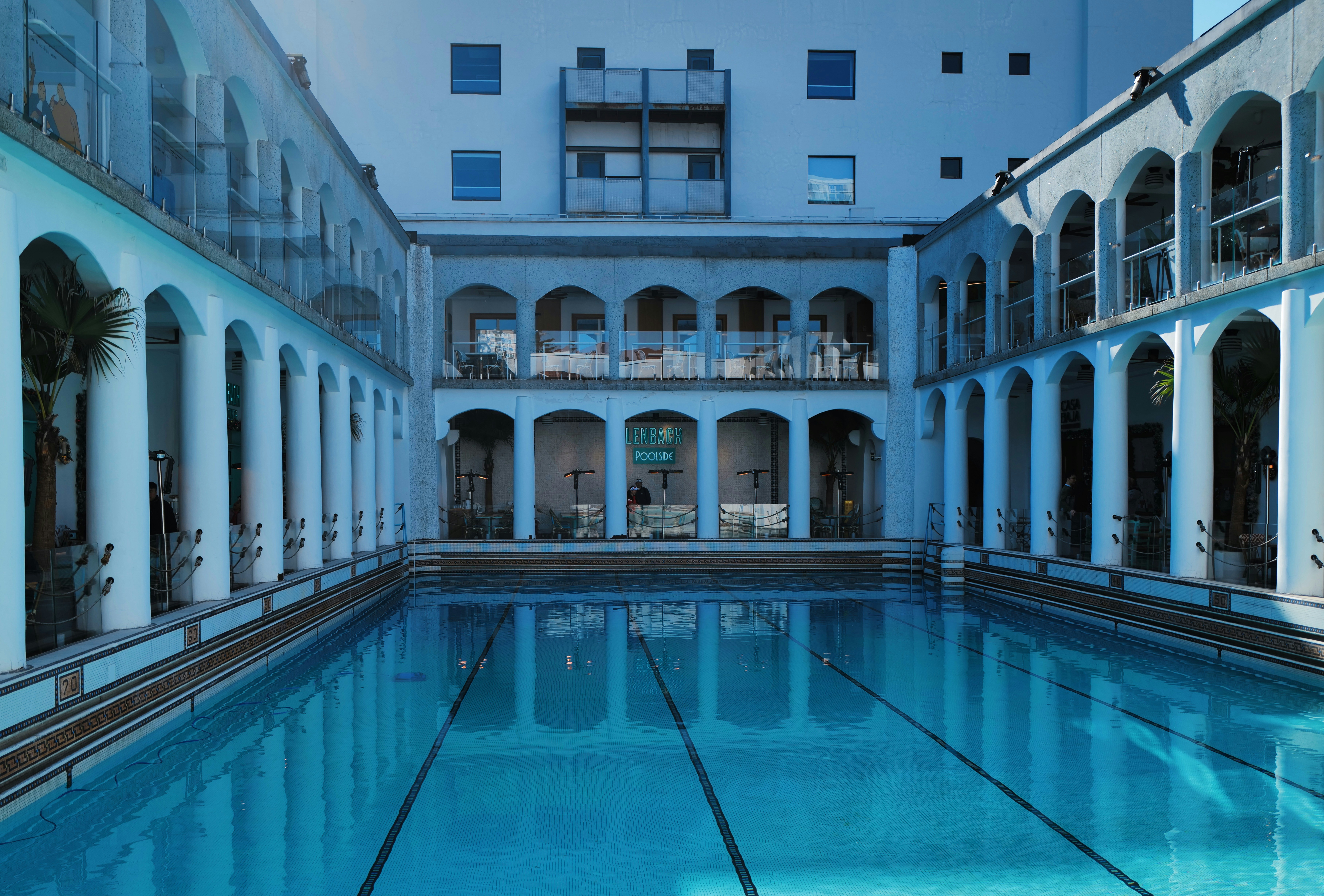 Blue-tinted Hotel Courtyard Pool Reflects a Symmetrical Arcadia