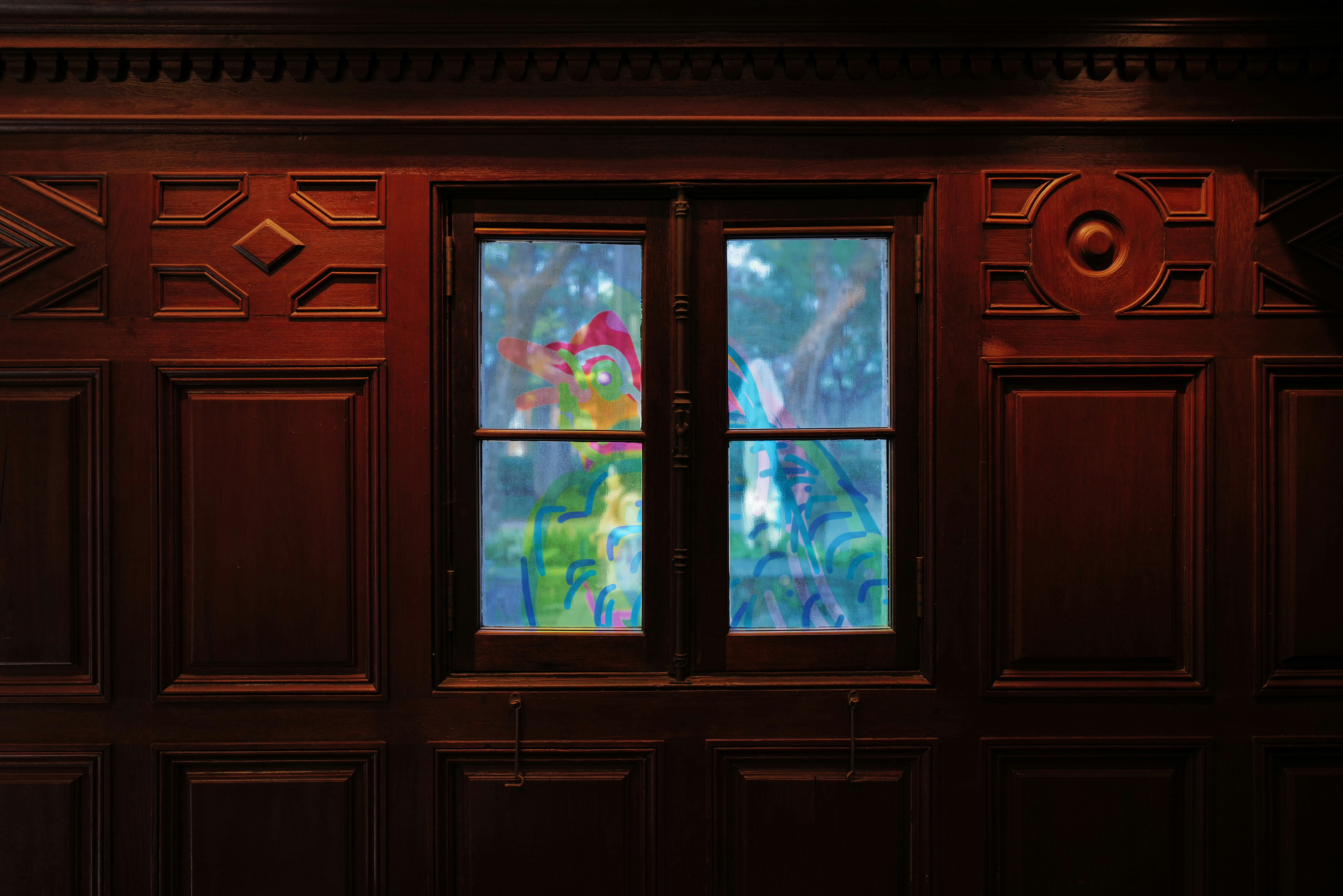 Hidden mural peeks through a wood-paneled window
