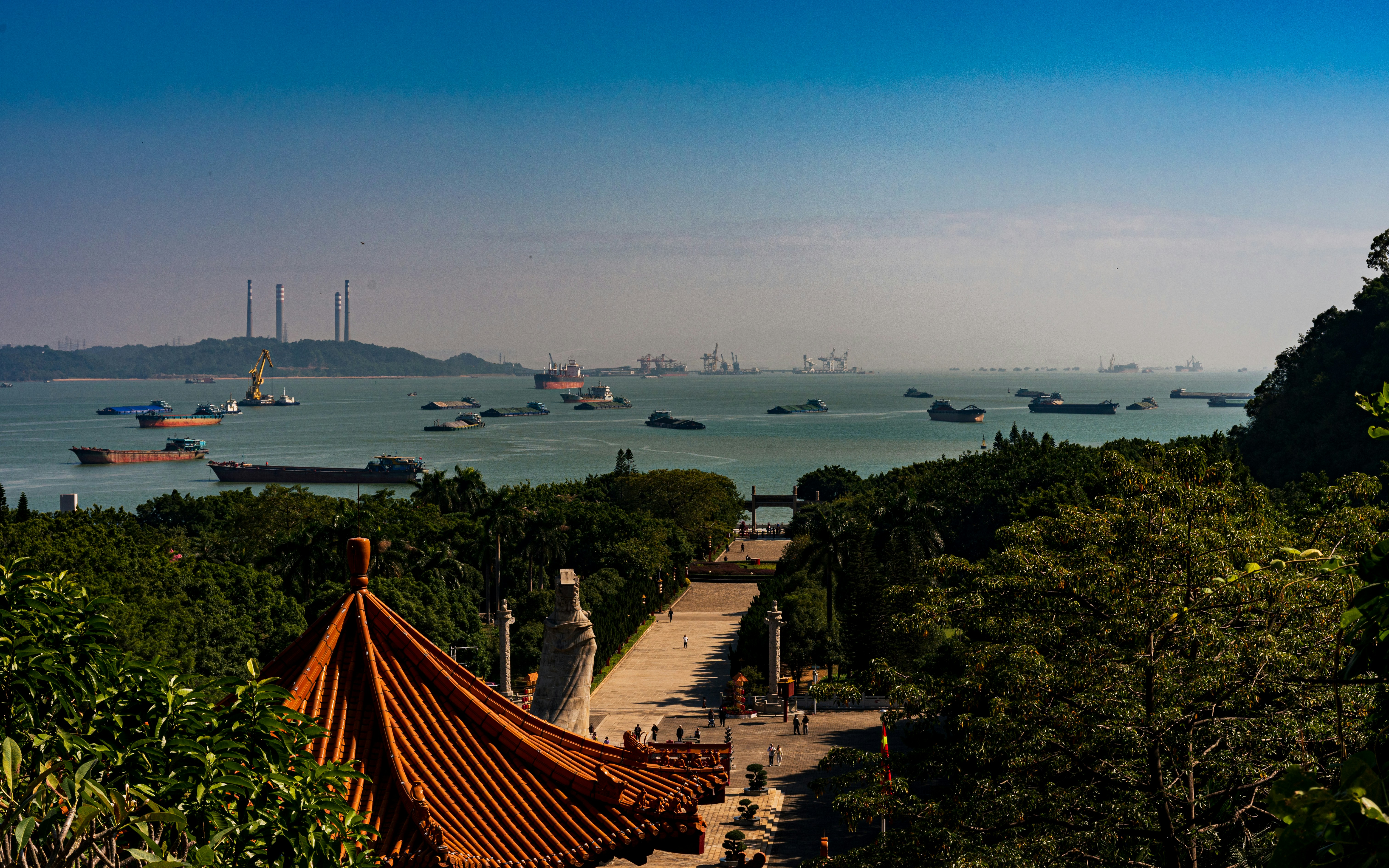 Harbor Vista: Boats at Rest Beyond a Traditional Rooftop and Verdant Promenade