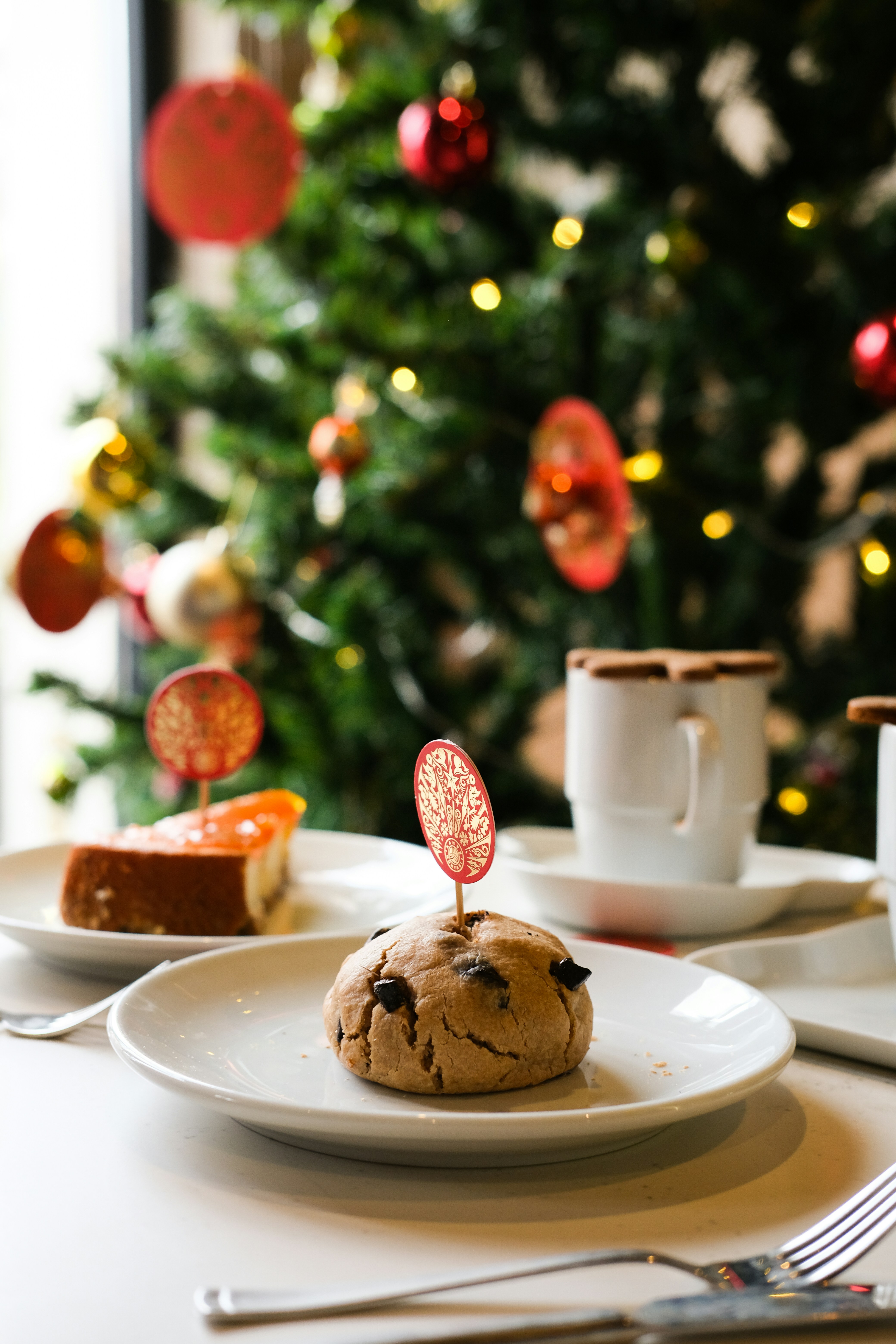 Central Holiday Dessert: A Chocolate Chip Cookie with a Red Fancy Pick in Front of a Festive Tree