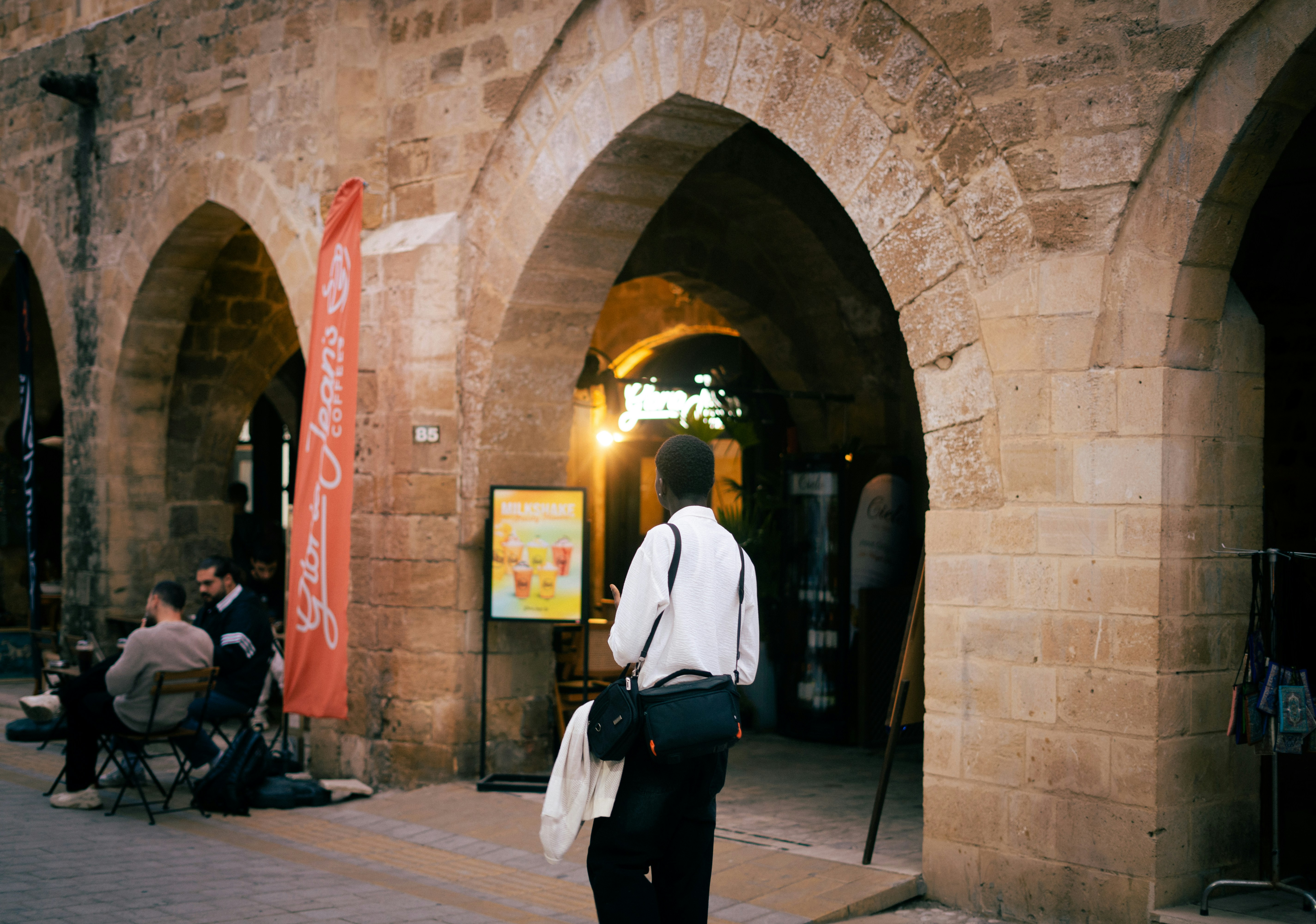 People sitting under stone arches in an old town. photo – Free Bag ...