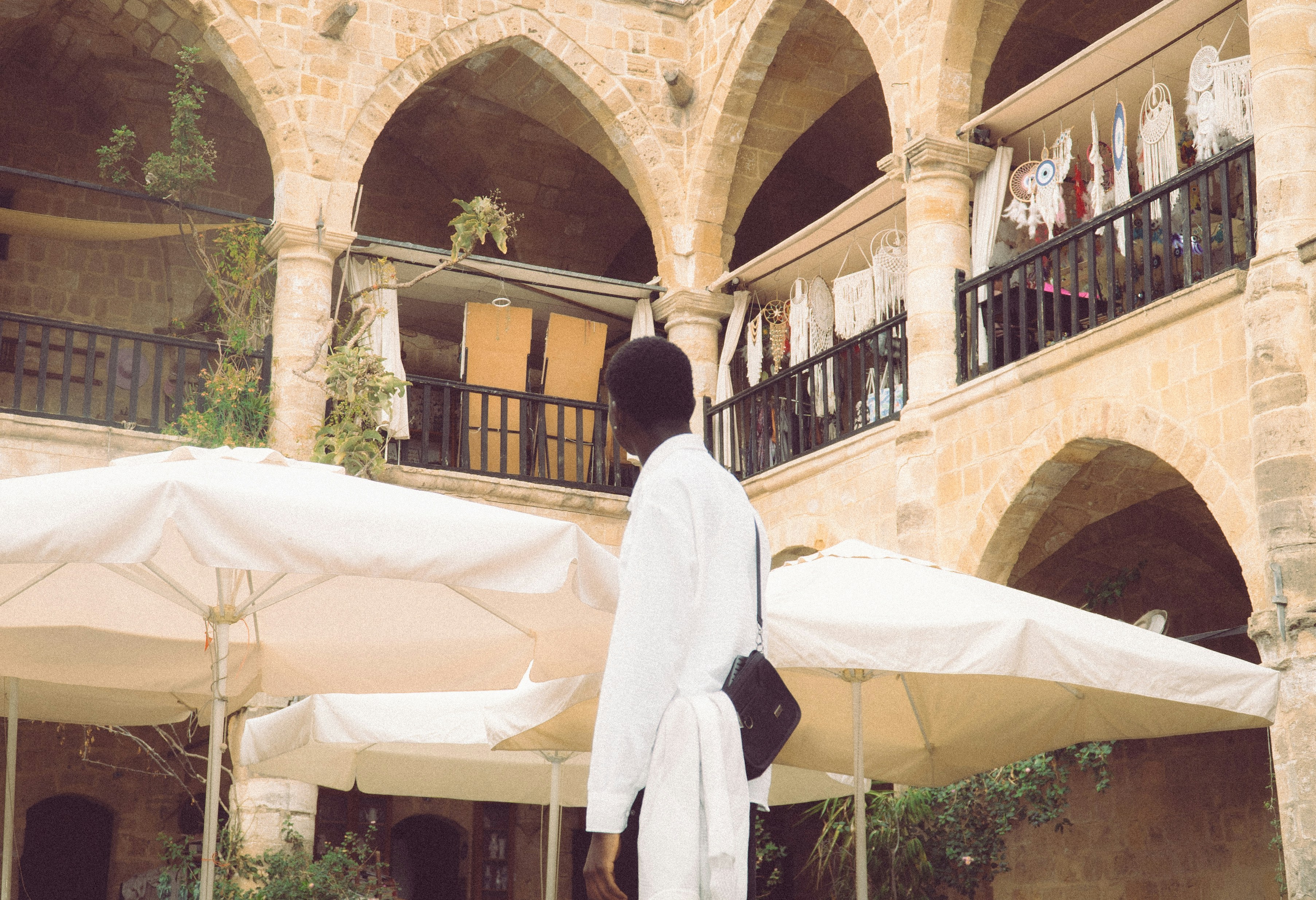 Courtyard Echoes: A Figure in White Amid Stone Arches