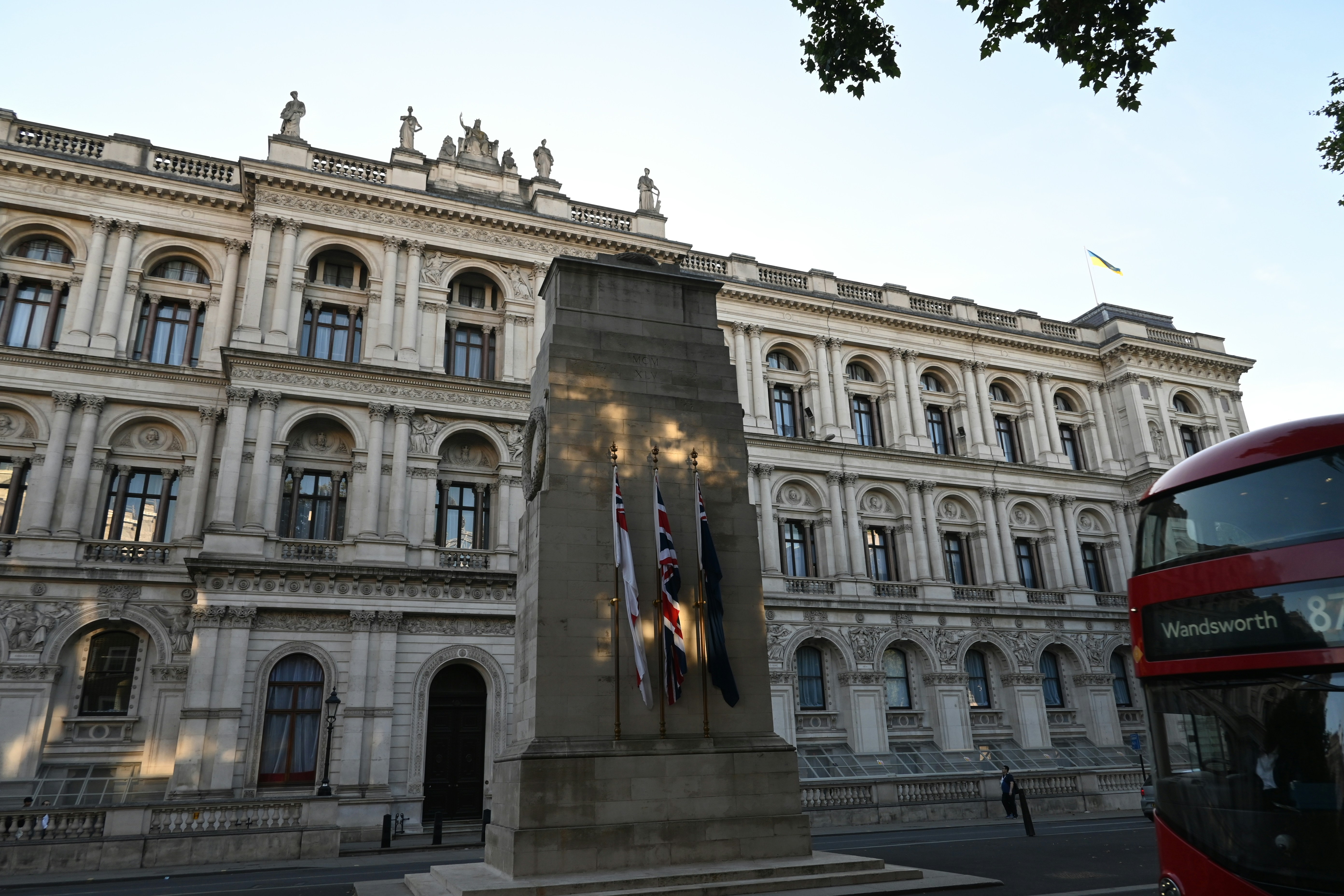 Monumental Facade and Red Prop bus: City Architecture with Flagpole Memorial