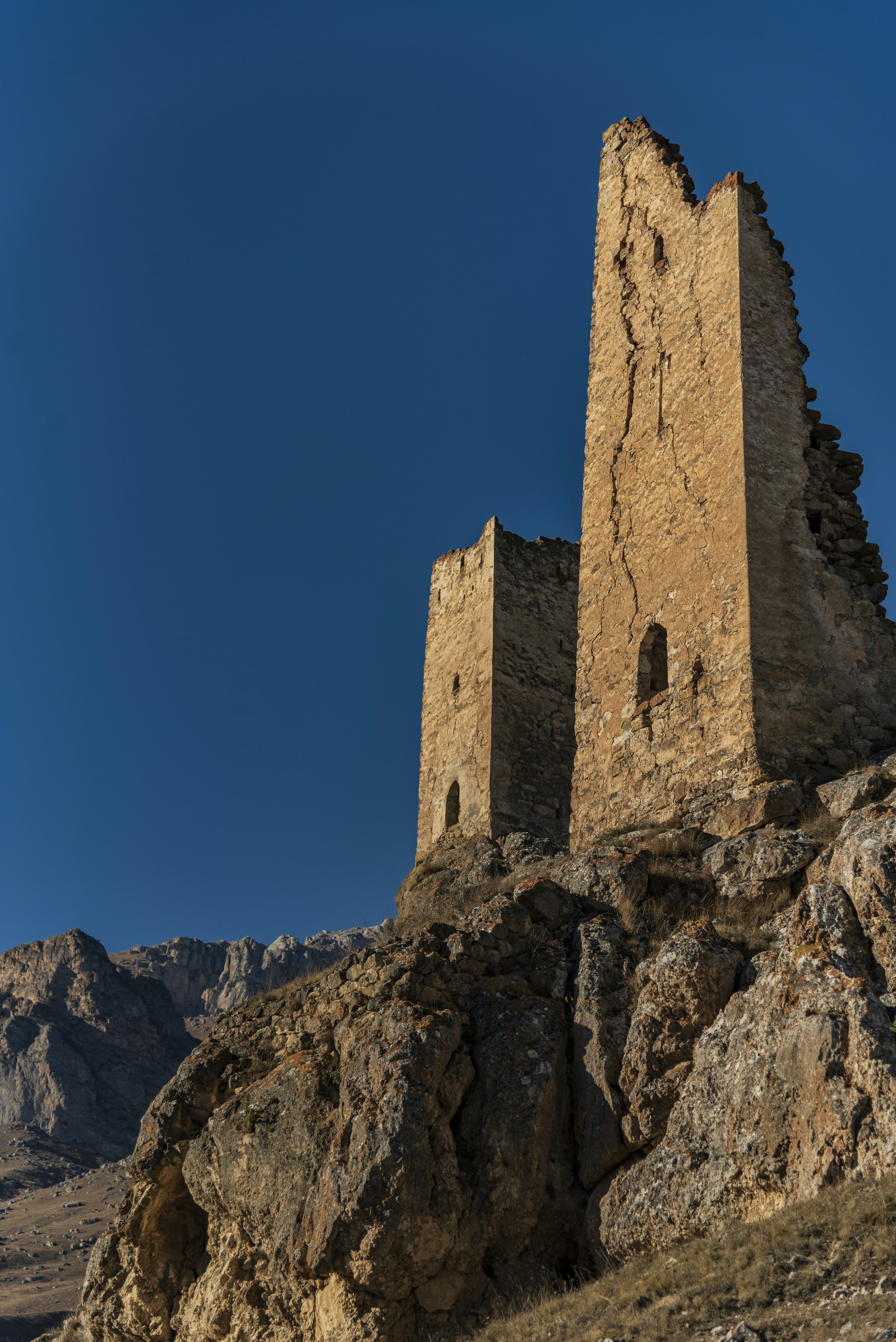 Stone Guardians on the Cliff: A Towering Ruin Beneath A Clear Blue Sky
