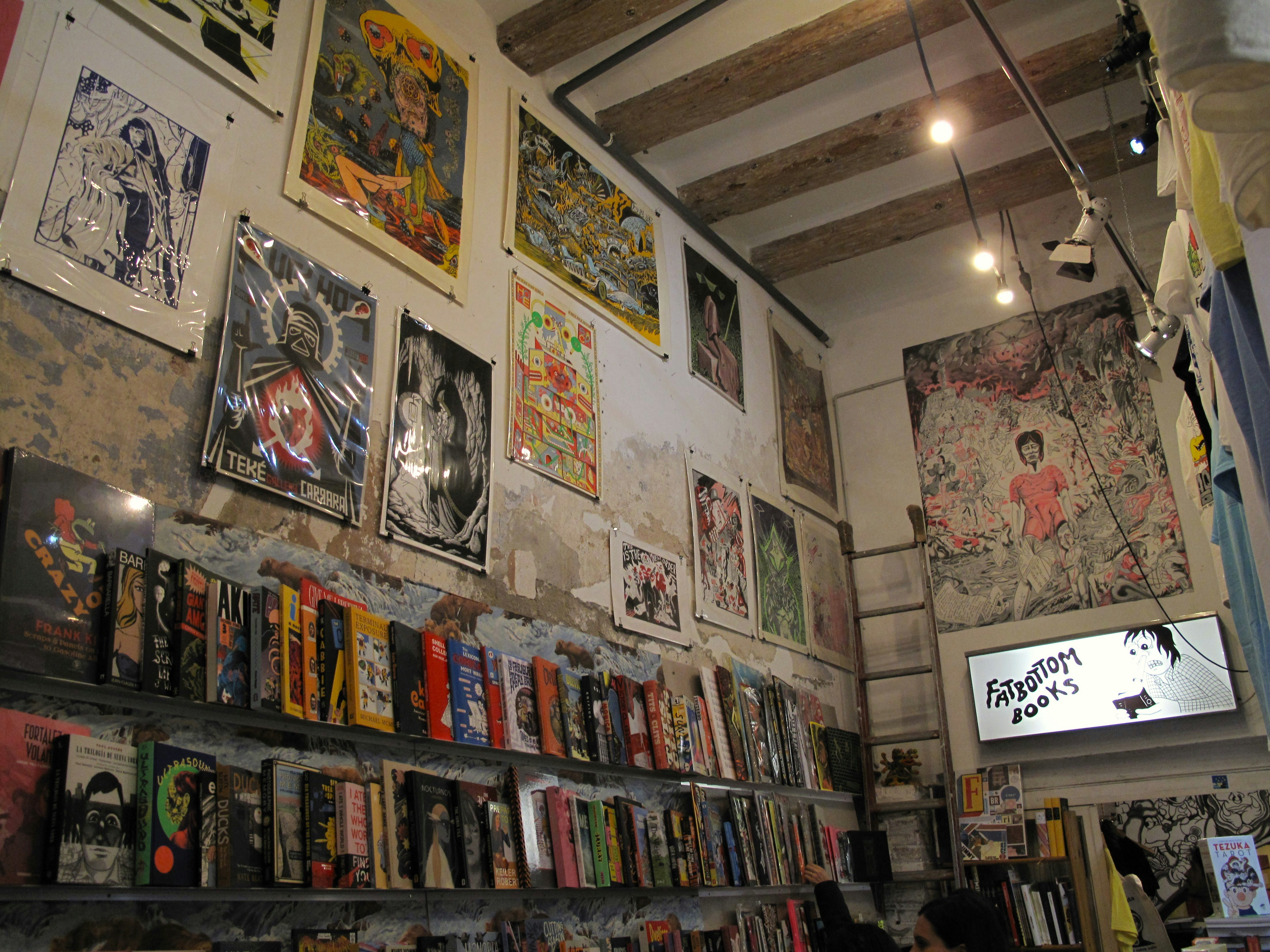Art prints and books displayed on a stone wall.