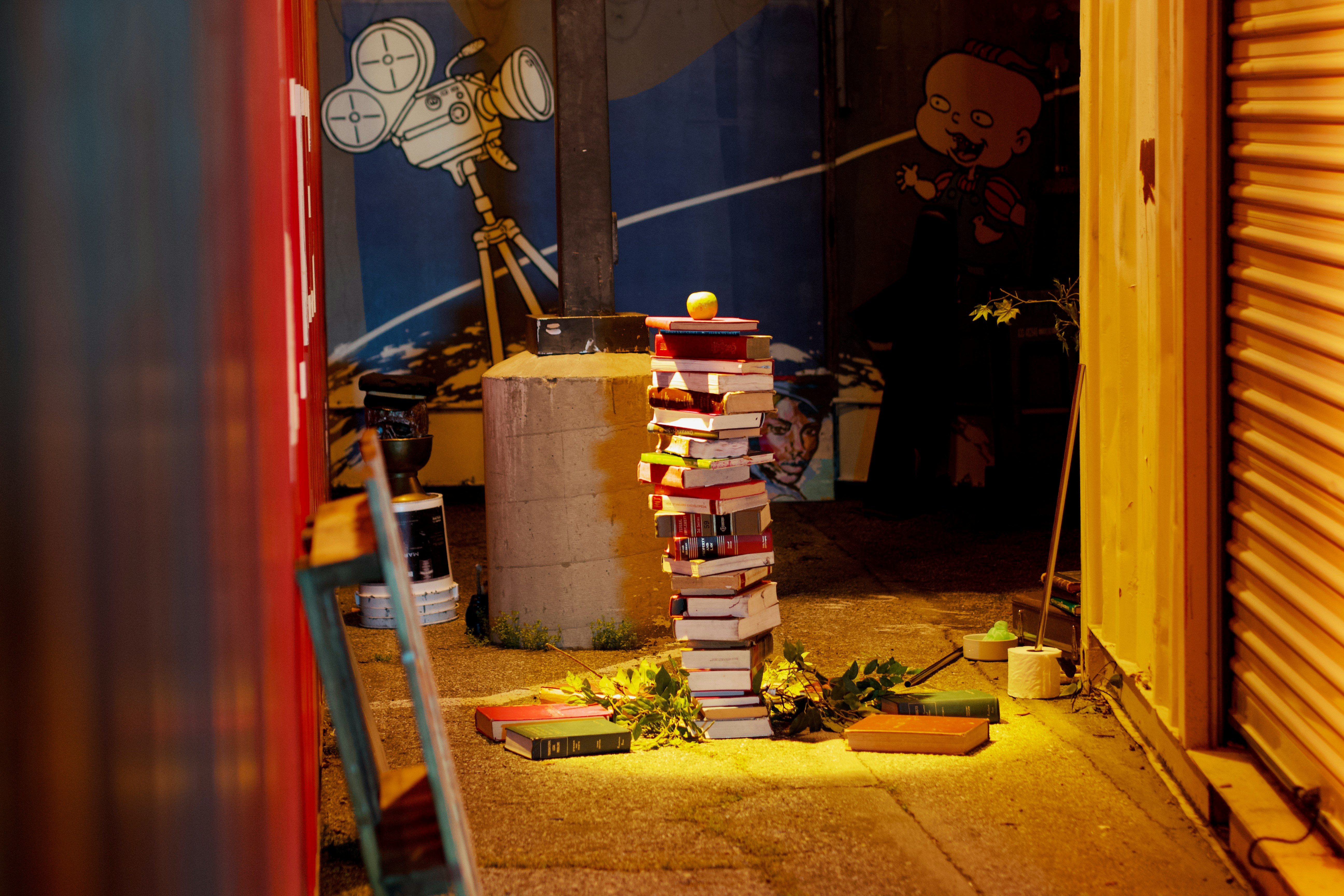 Stacked books glow under a warm alleyway lamp