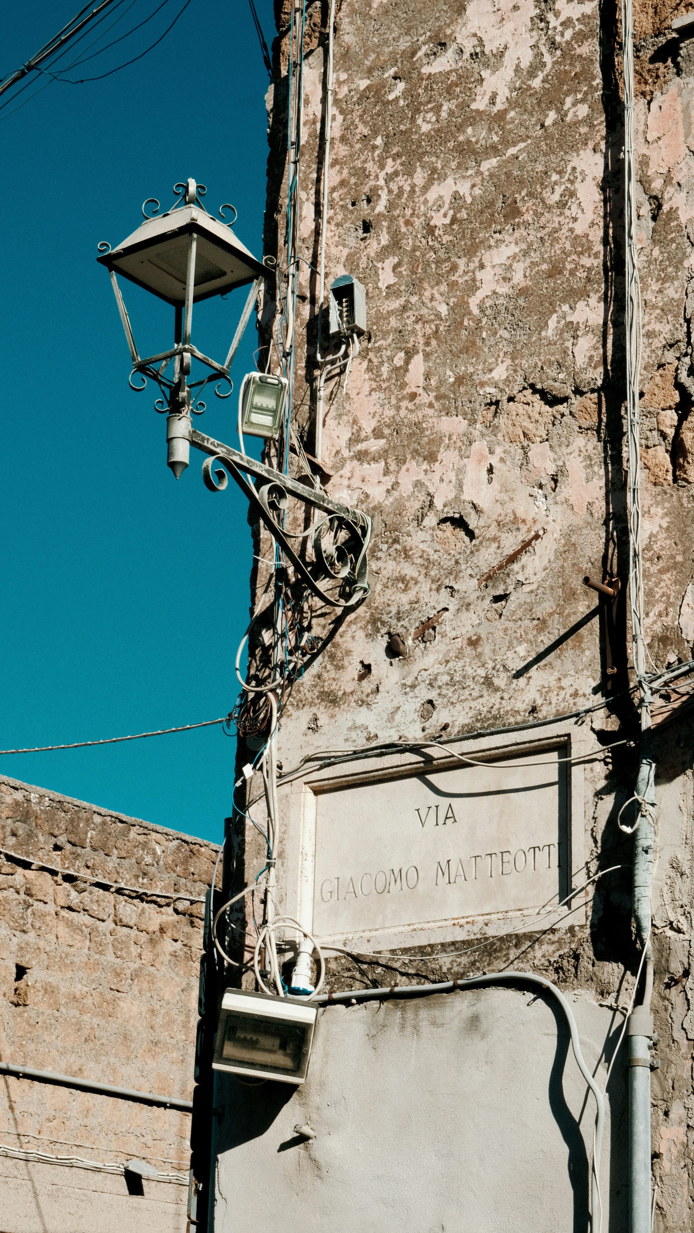 Crumbled Facade on a Sunlit Via with Vintage Street Lamp