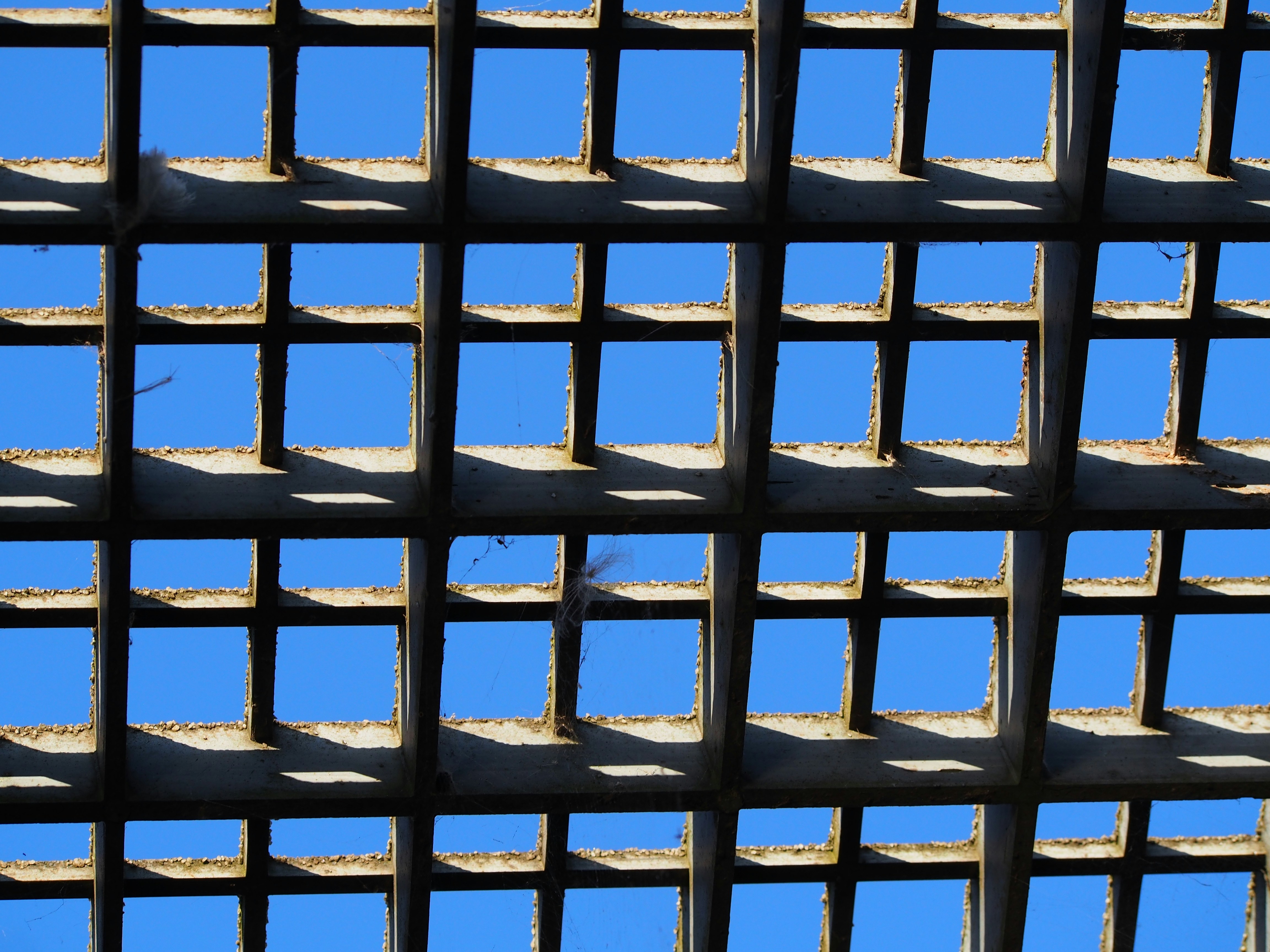 Blue Sky Through Geometric Grids: An Abstract Metal Lattice