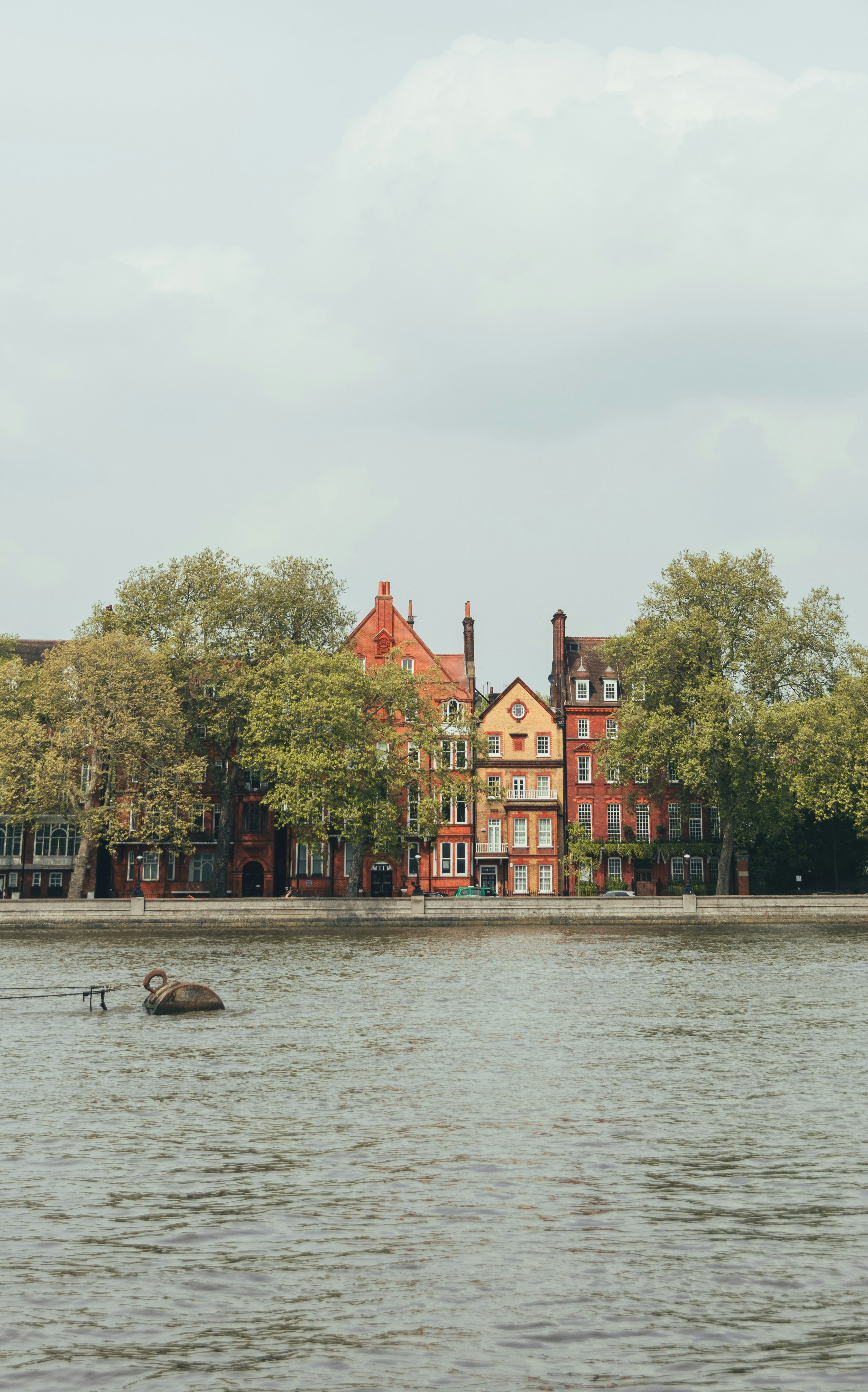 Colorful townhouses by the riverfront under a pale sky