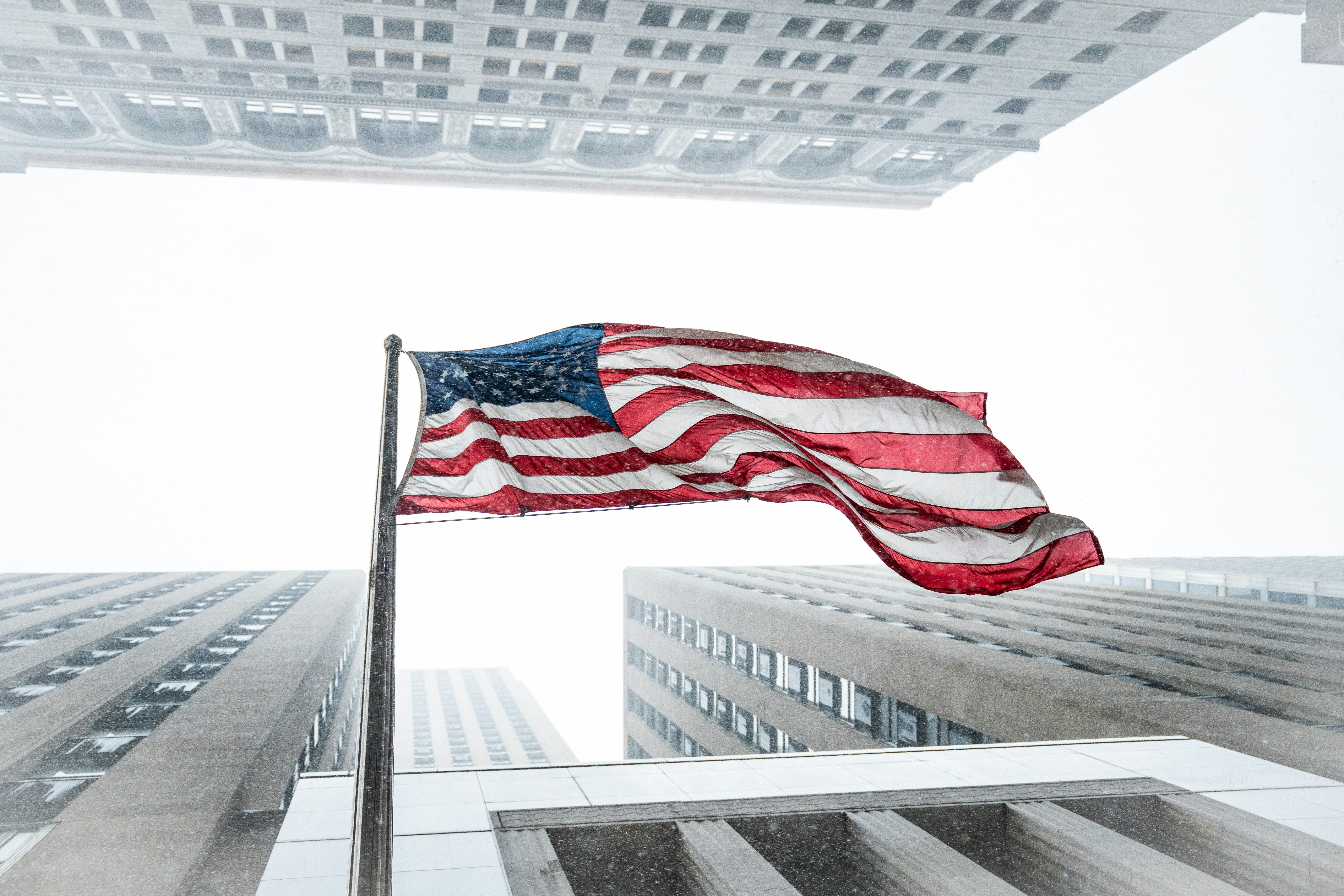A flag waves as the camera looks up amidst skyscrapers
