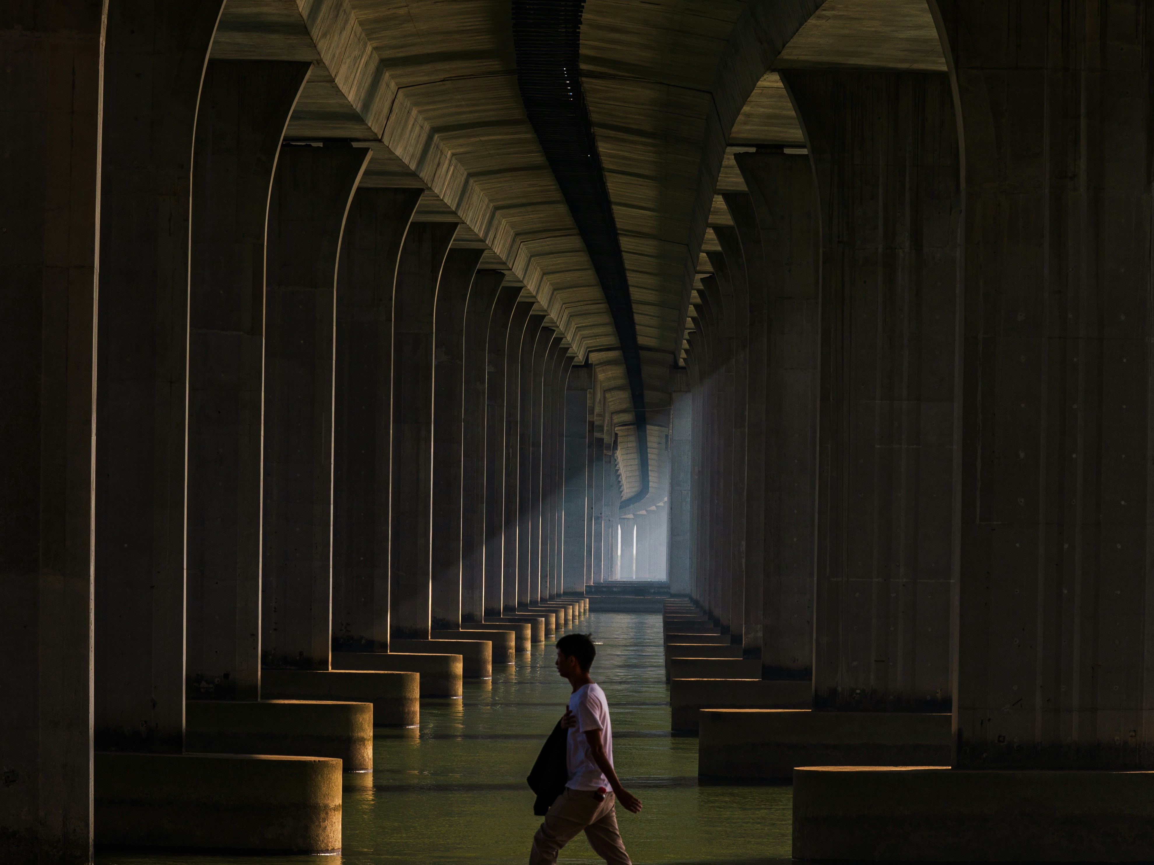  lone traveler under the concrete arches toward the light