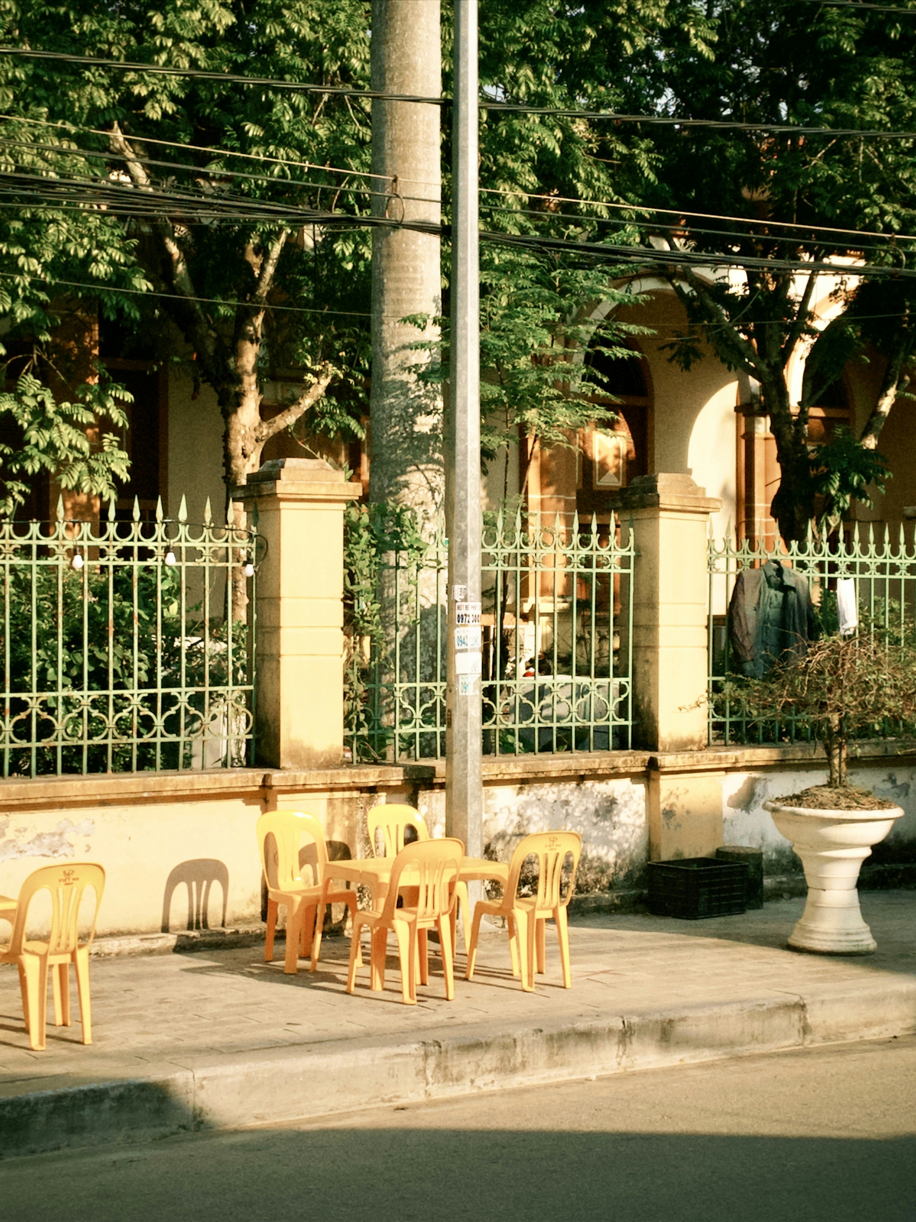 Yellow Chairs on the Sidewalk by a Walled Garden