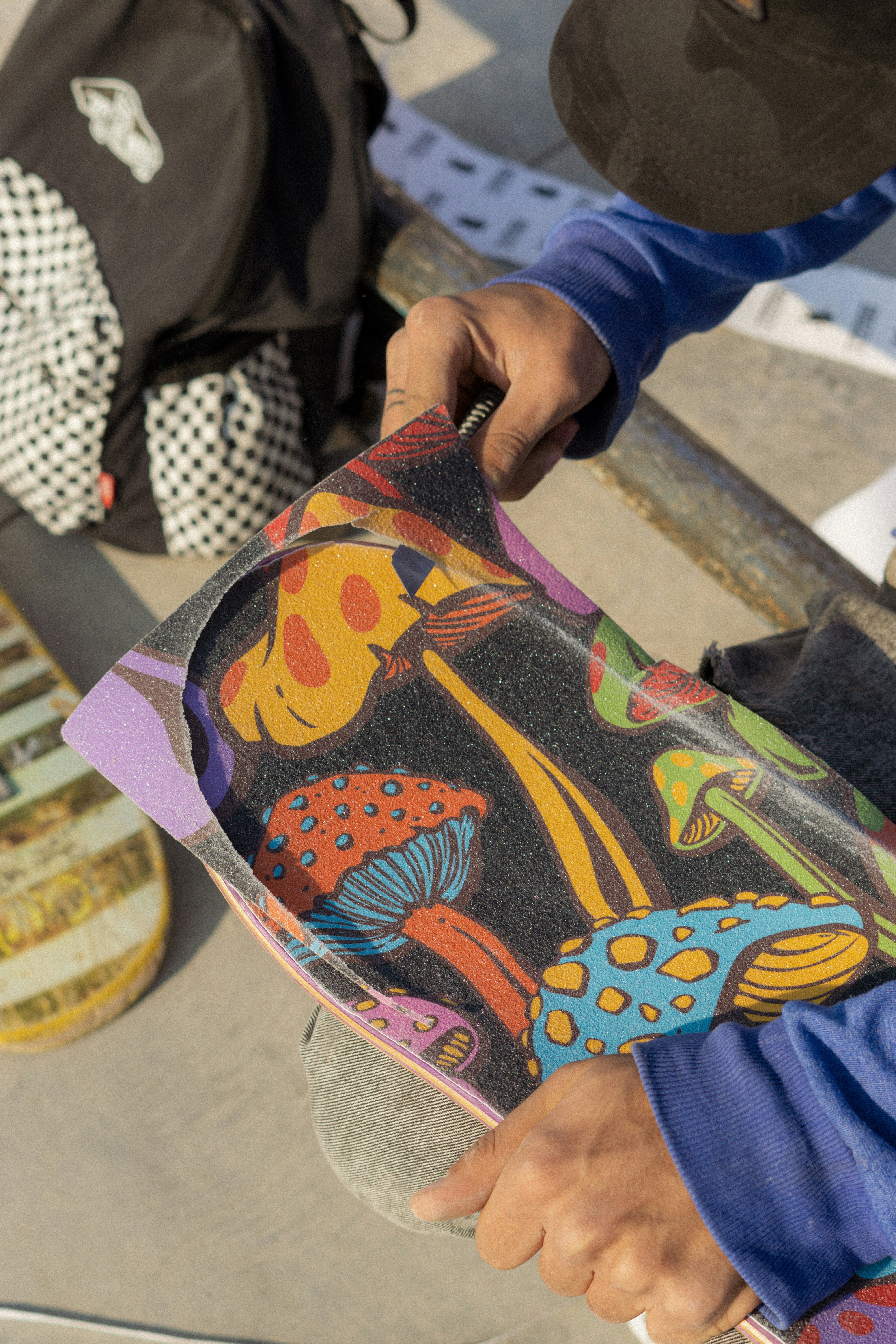 Colorful skateboard grip with mushroom motif held over a bench