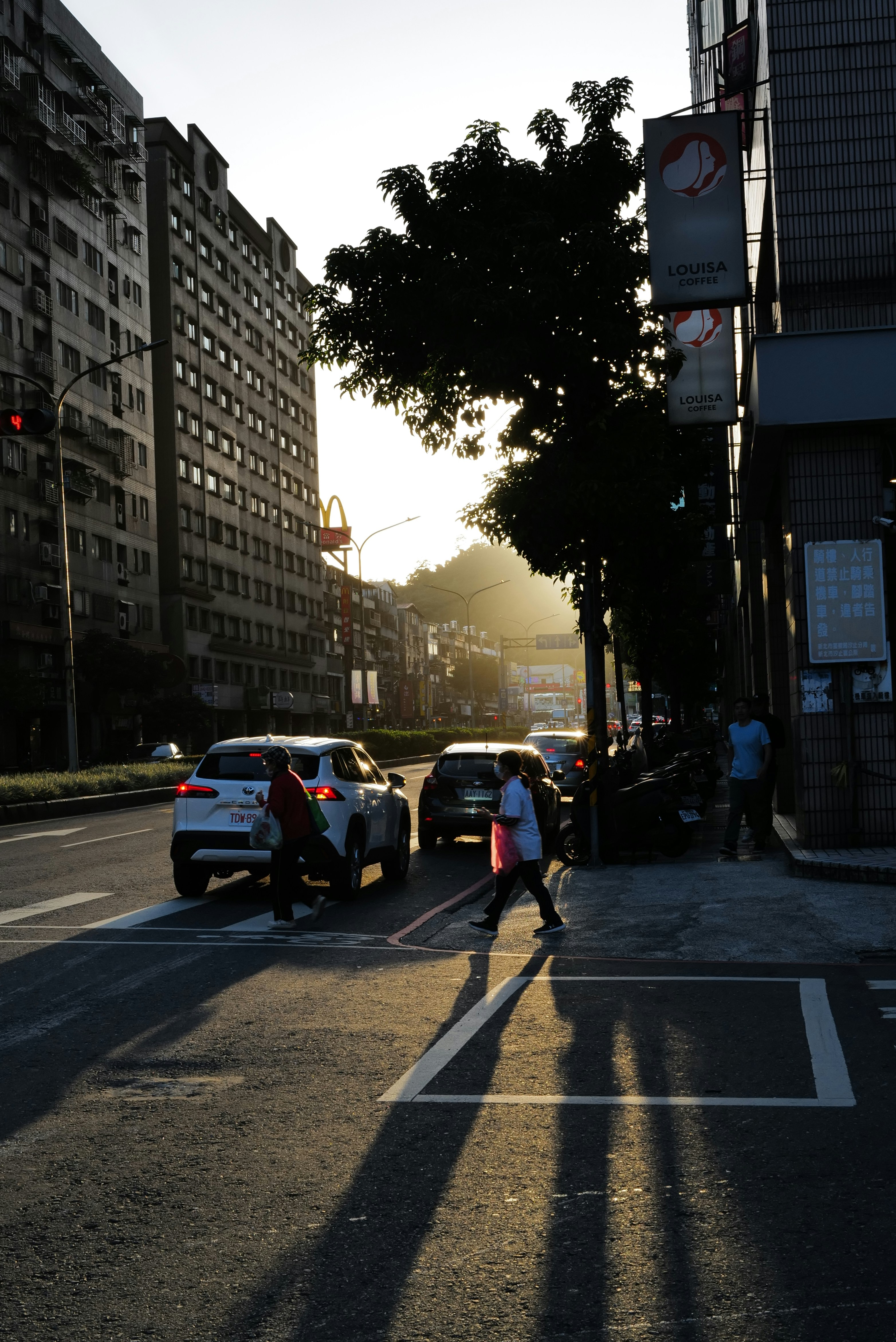 City Crosswalk at Sunset: Pedestrians, Long Shadows and a Glowing Street Scene