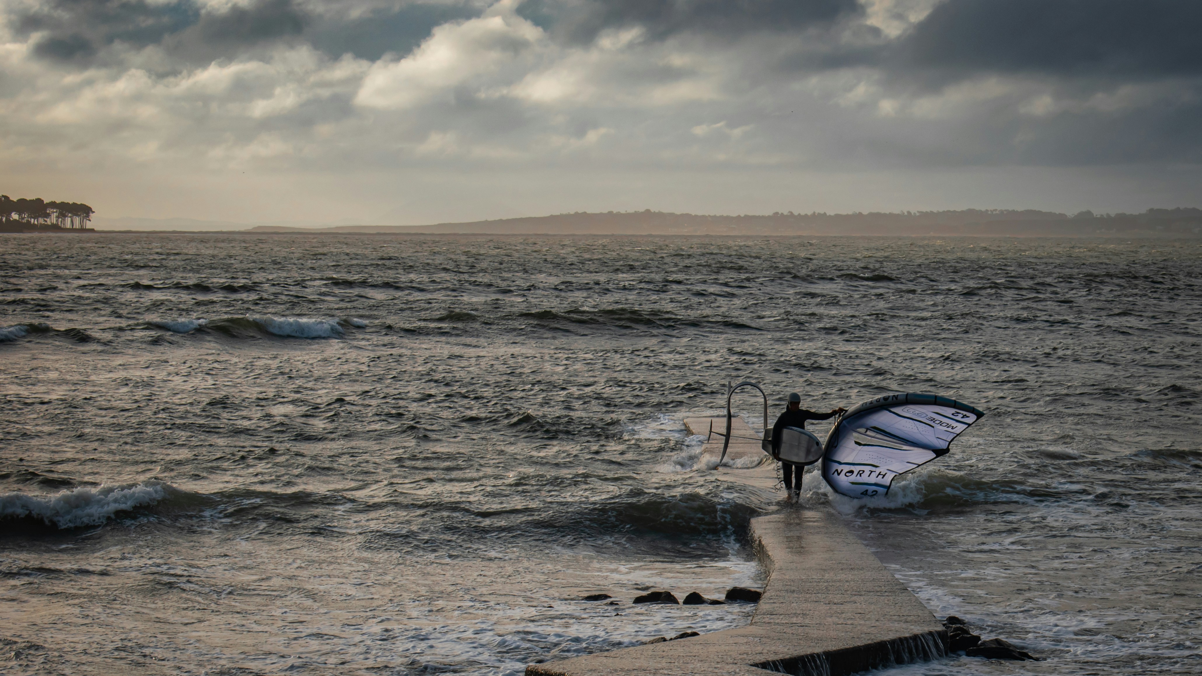 Surfer at the Pier: Evening Glide into Aerial Haze