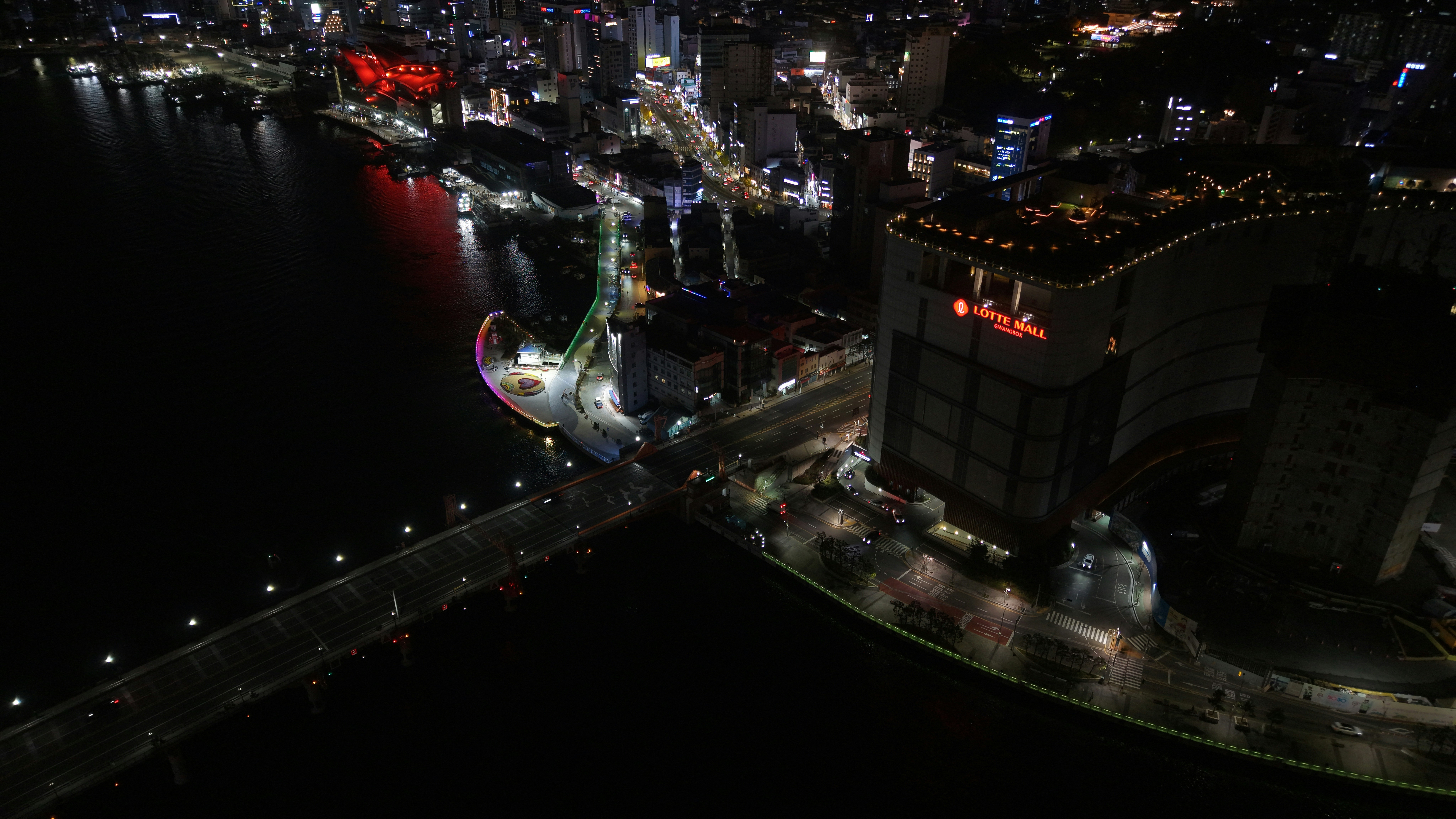 Neon Riverfront After Dark: Aerial View of a City Bridge and Lit Waterfront