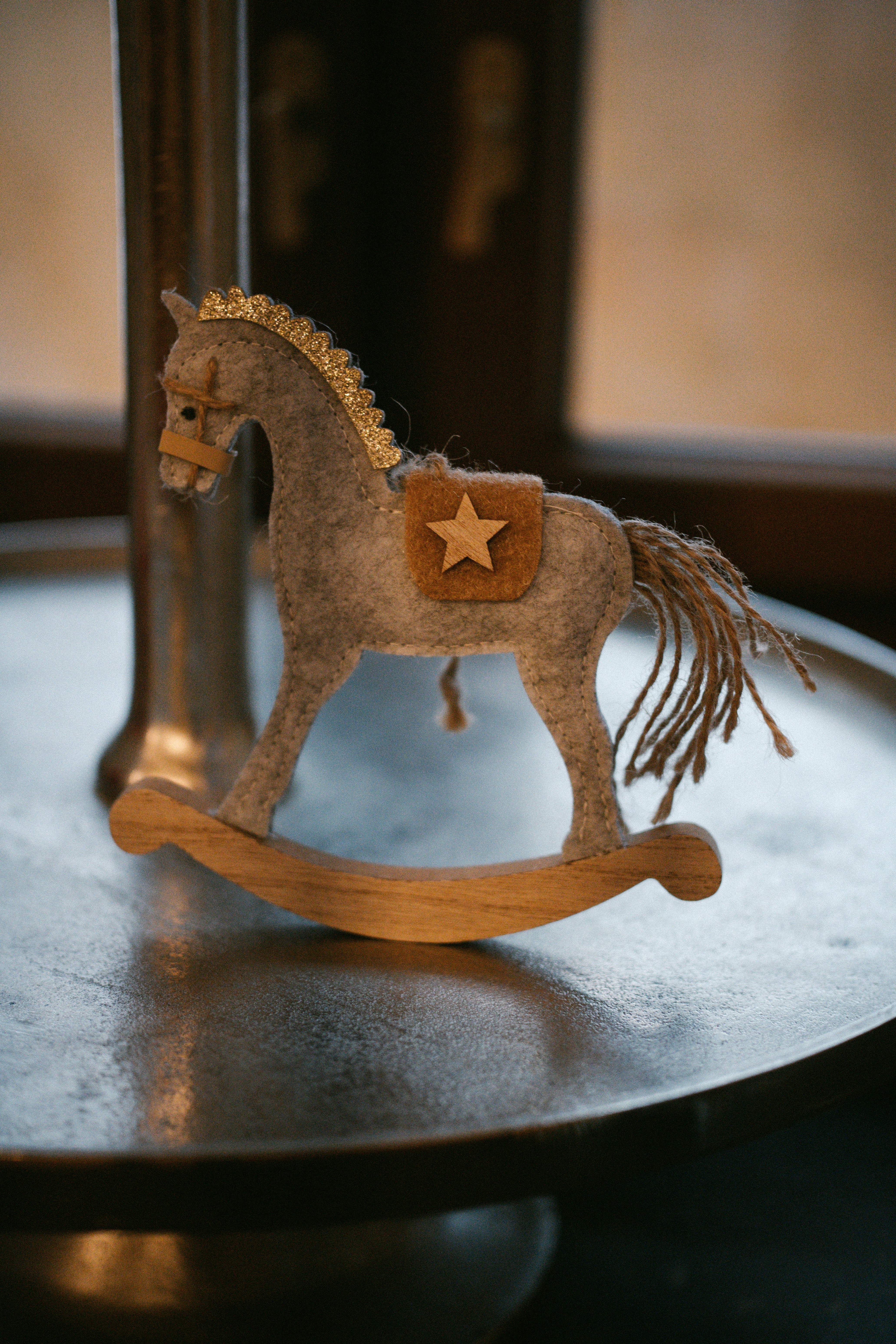 A felt rocking horse ornament with a wooden base.