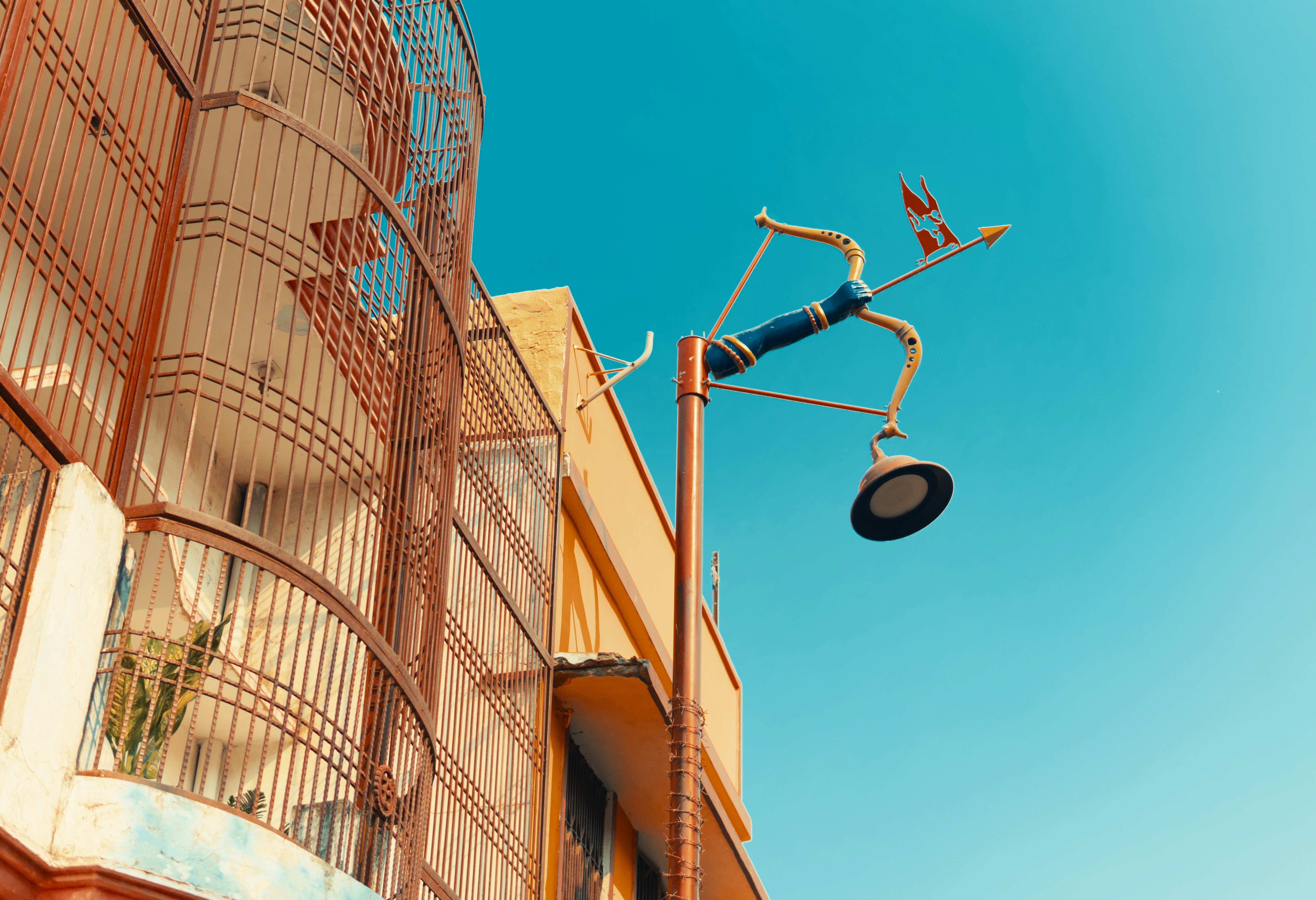 Opposing Skyward Arc: A street lamp defies gravity against a sunlit urban facade