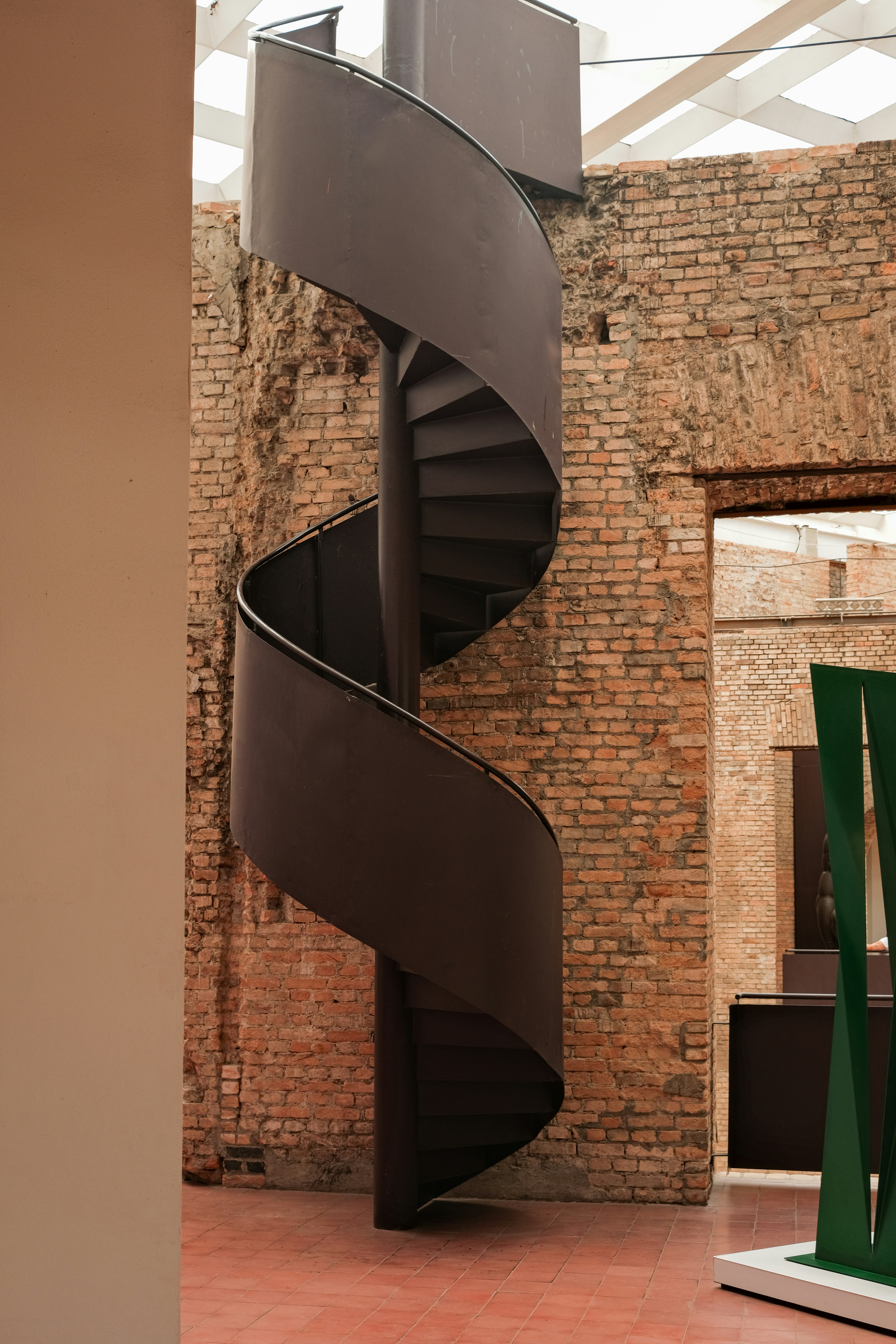 Spiral Iron Staircase Winding Through Brick Hall