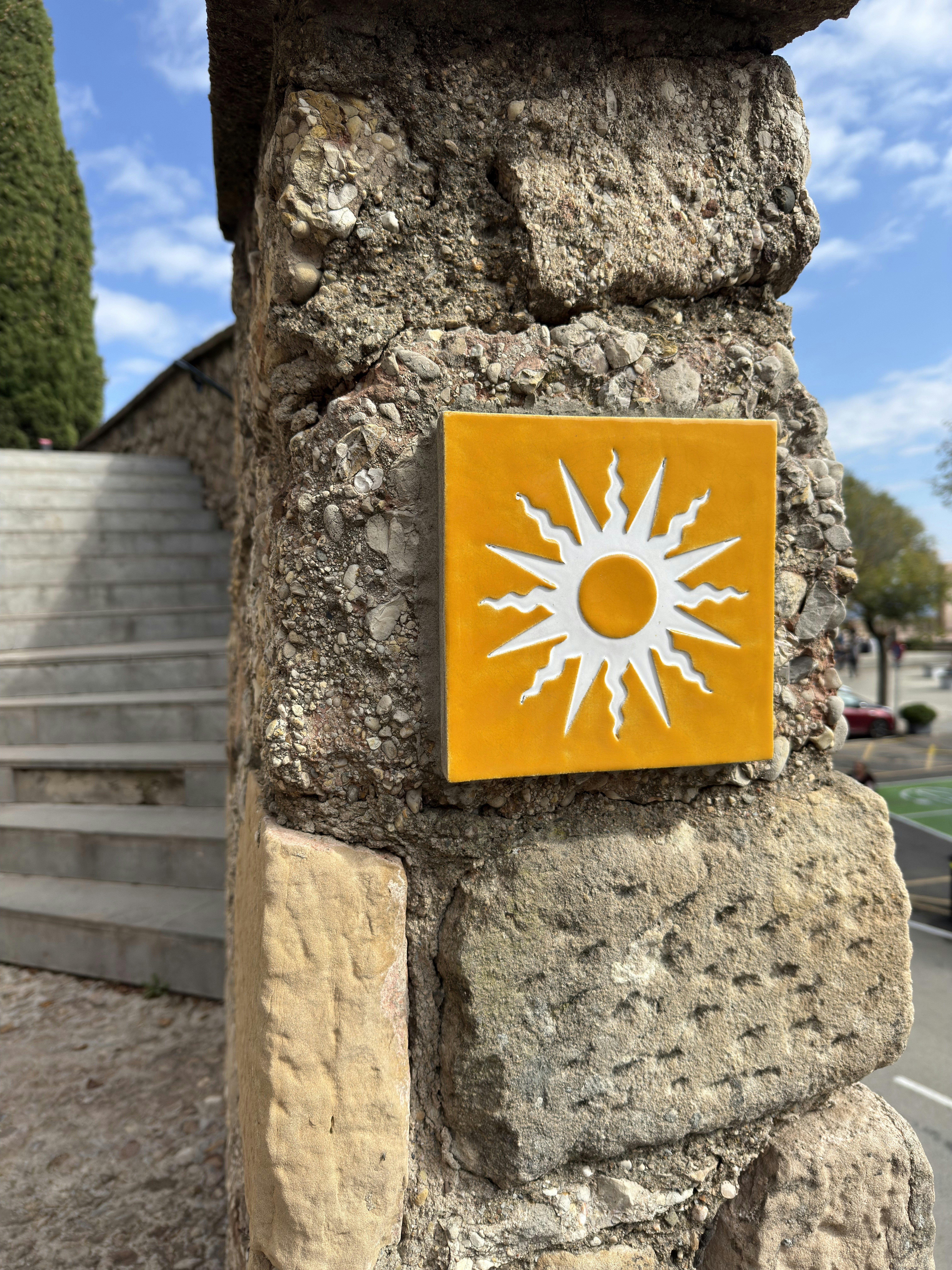 Sunlit emblem on rugged stone: a bright tile in a graded archway