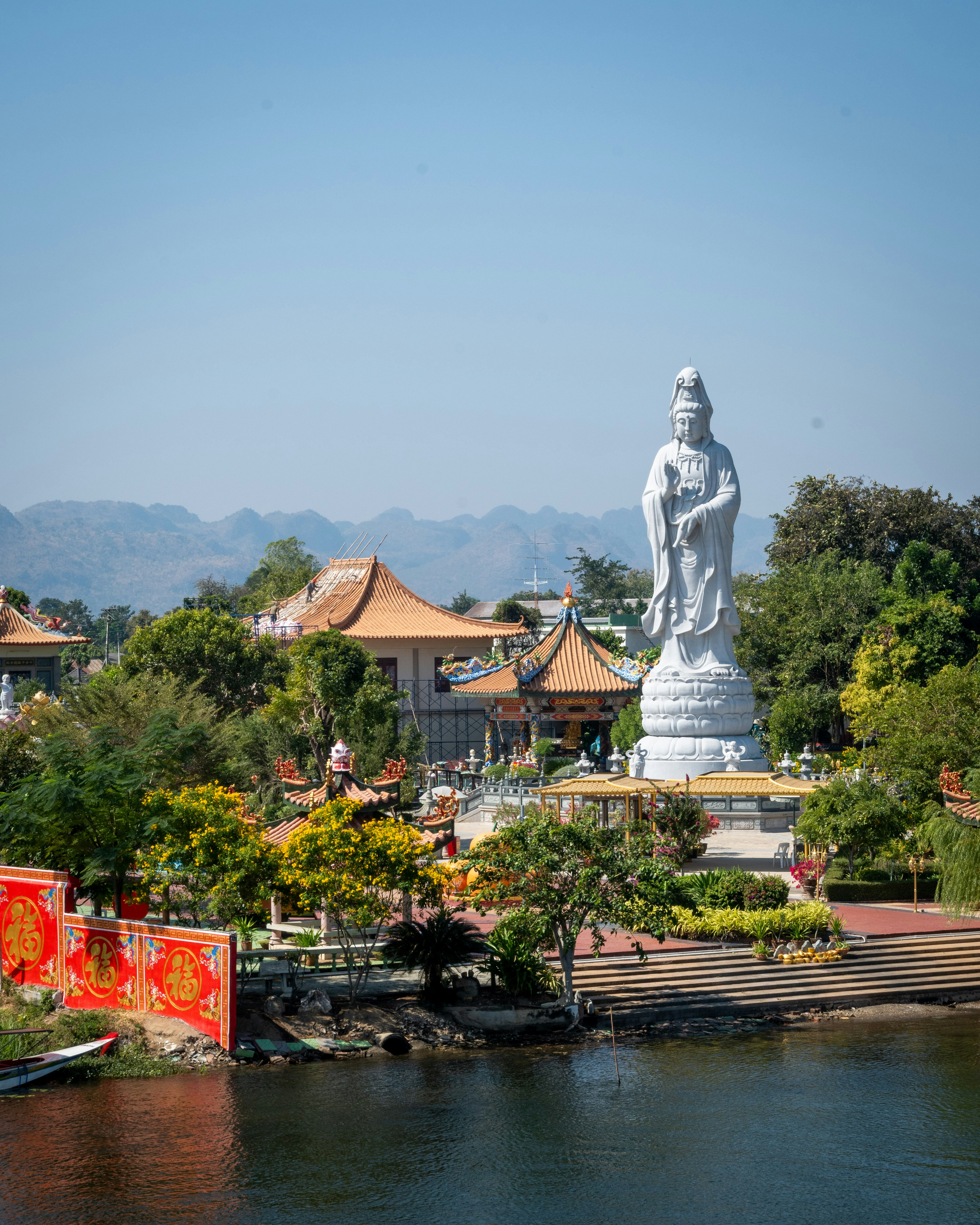 Guardian of the Shoreline: A Serene Temple Vista with a Grand Statue