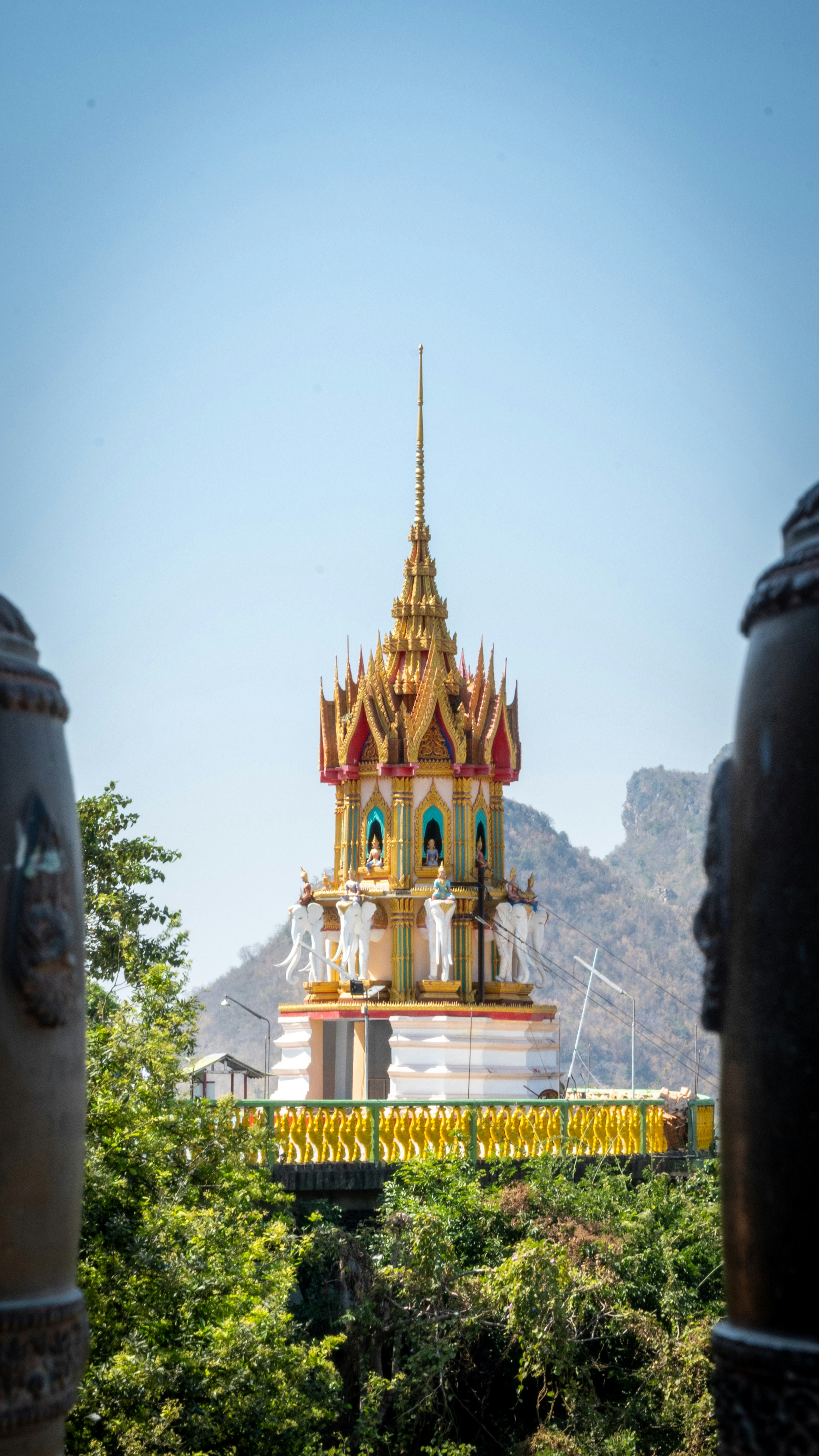 Golden Tower Rising Above Greenery and Distant Mountains