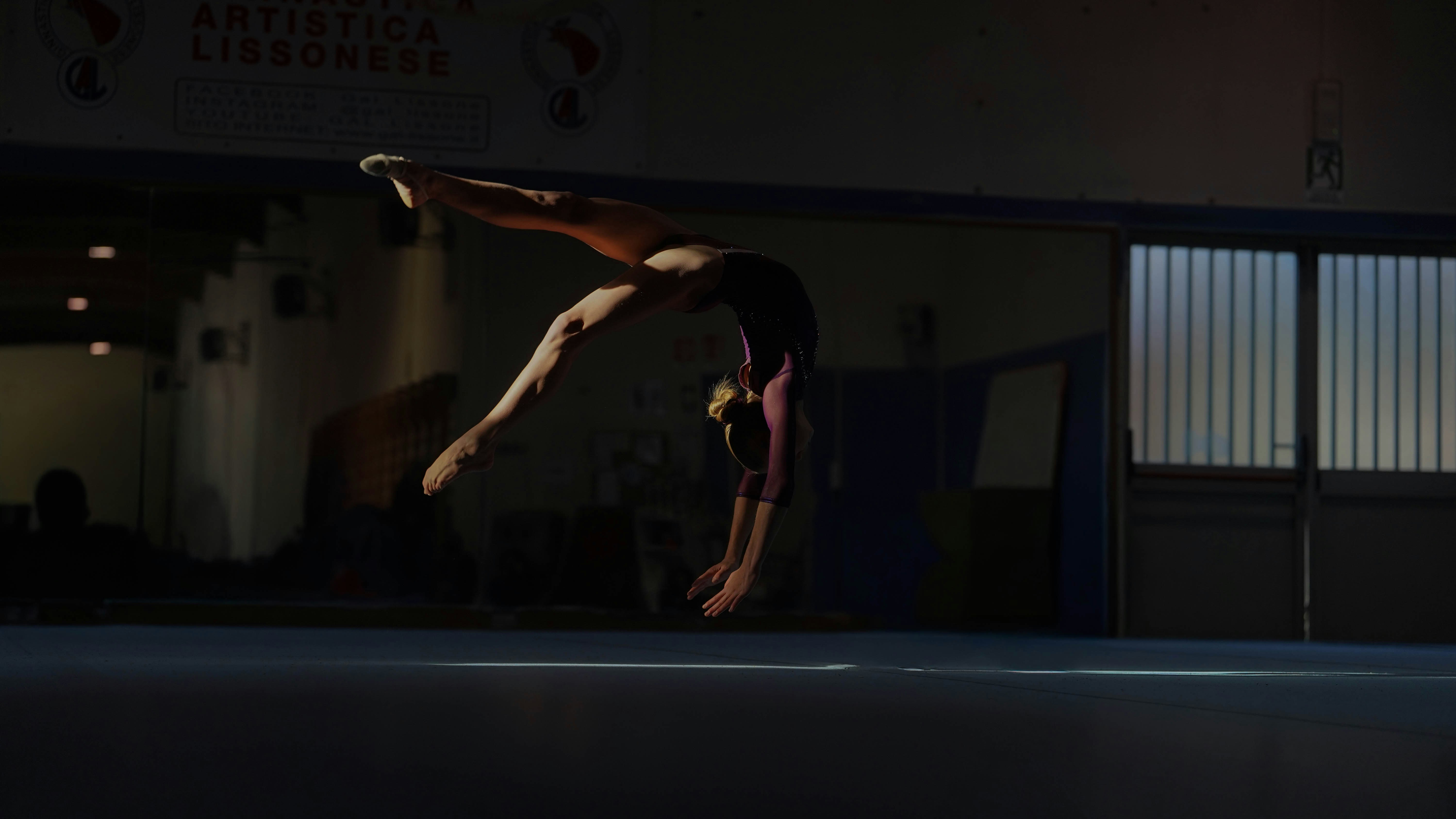 Midair Silence: A Dancer Halts at the Edge of the Pool of Light