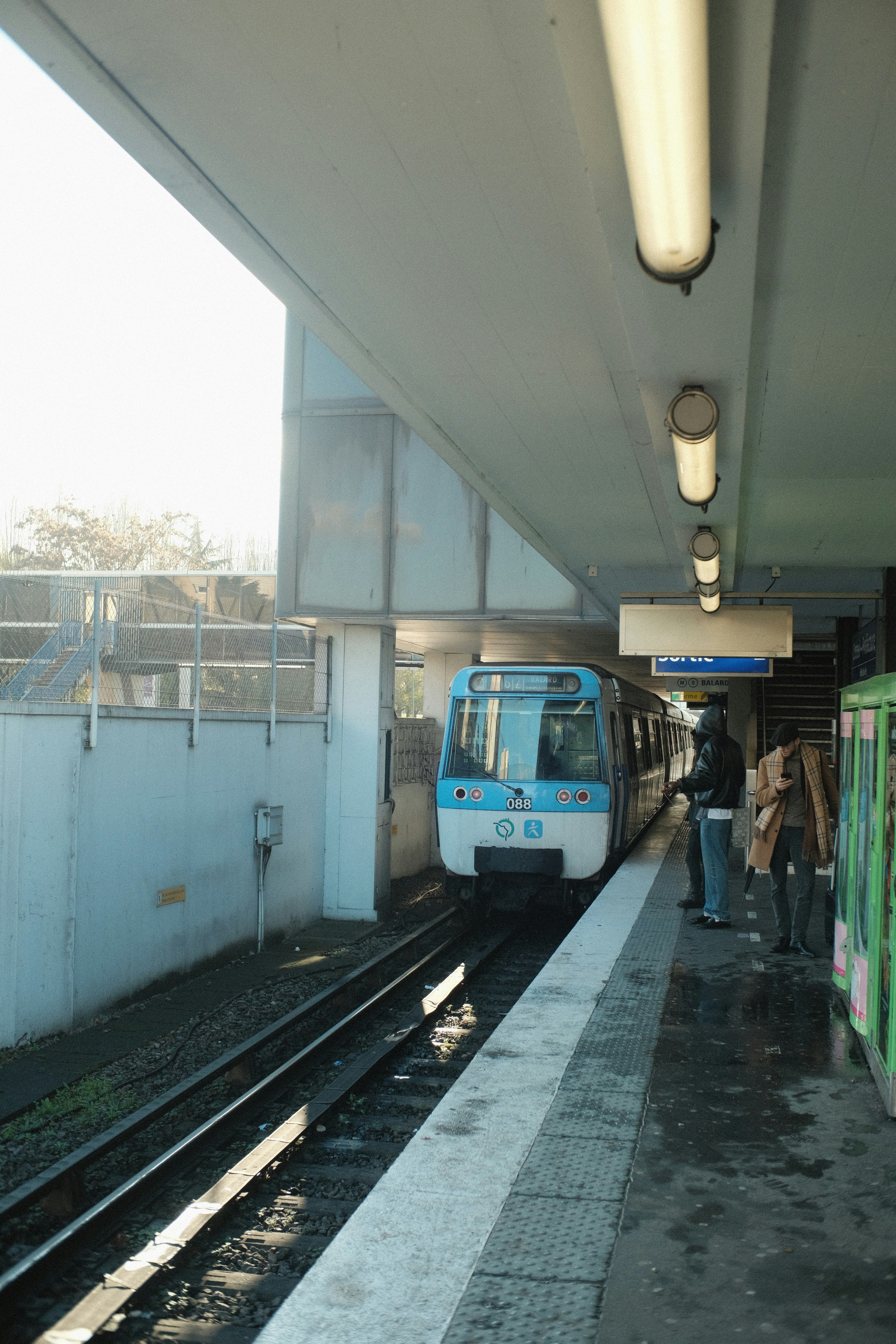 Platform Edge Encounter: Blue Commuter at Distant Stop