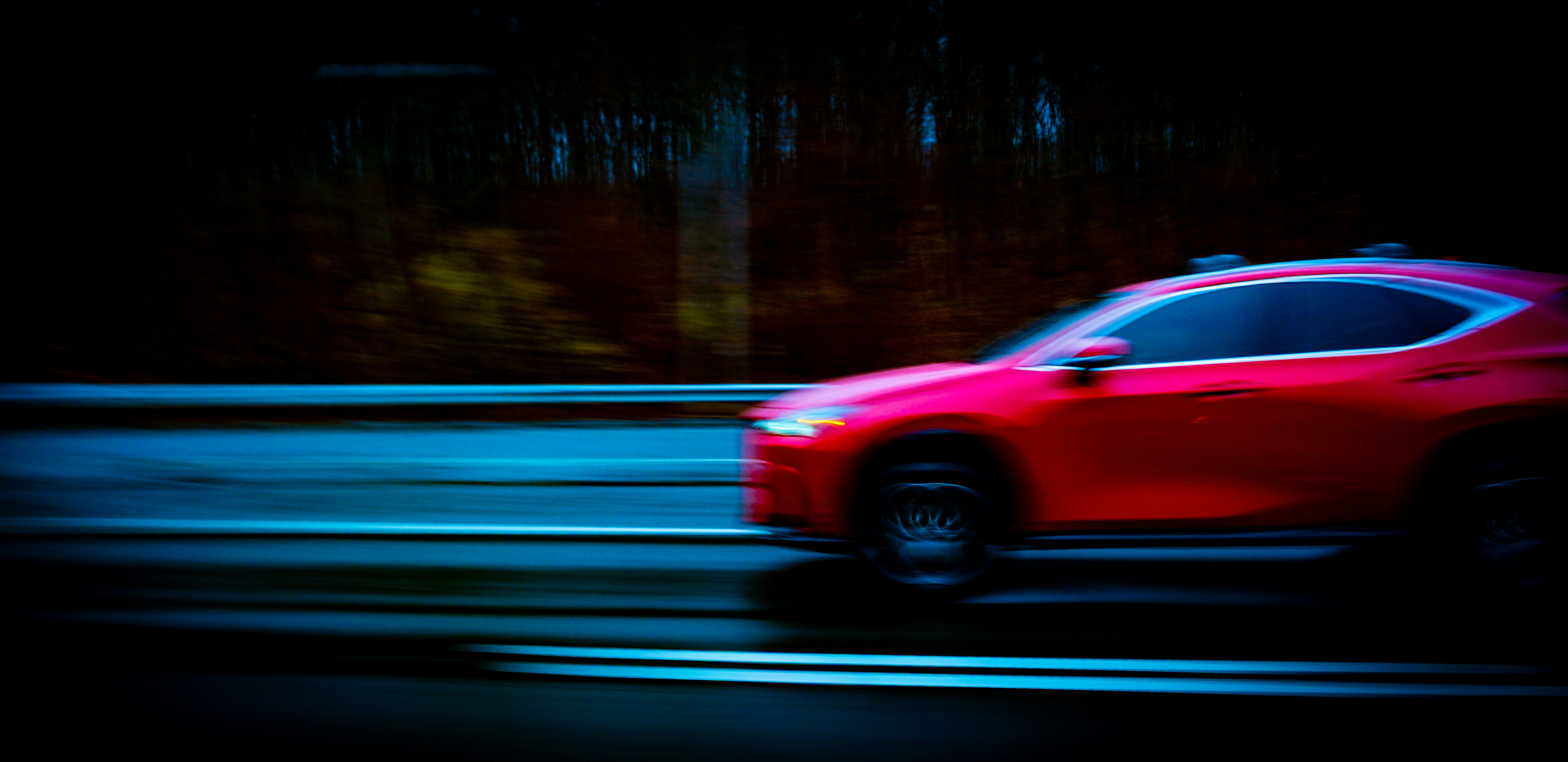 Blazing Red Blur: A Red Sedan in a Low-Light Highway Push