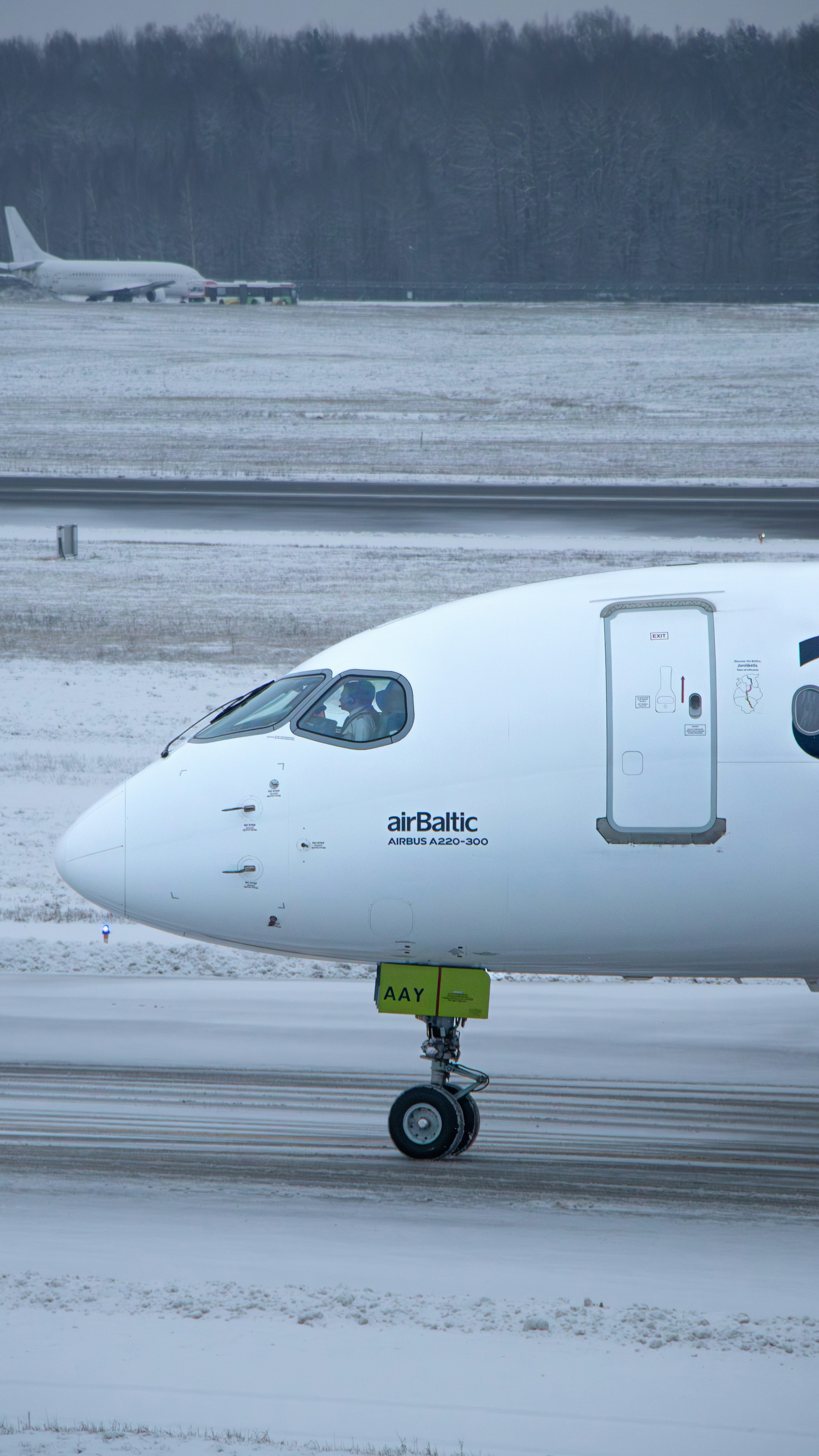 Front Nose of an AirBaltic A220-300 at Rest on Icy Ramp