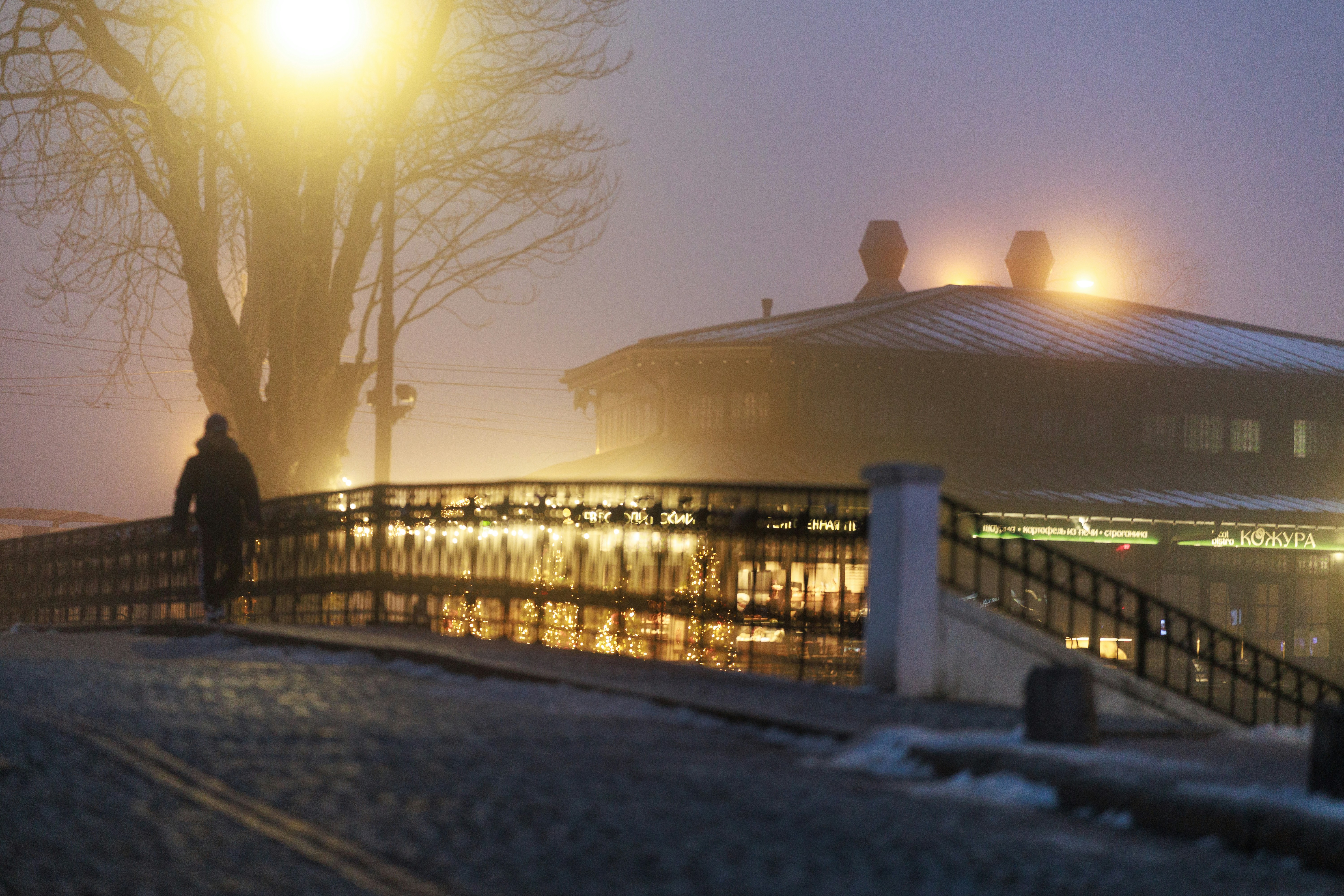Foggy Riverside Evening with Lantern-lit Bridge