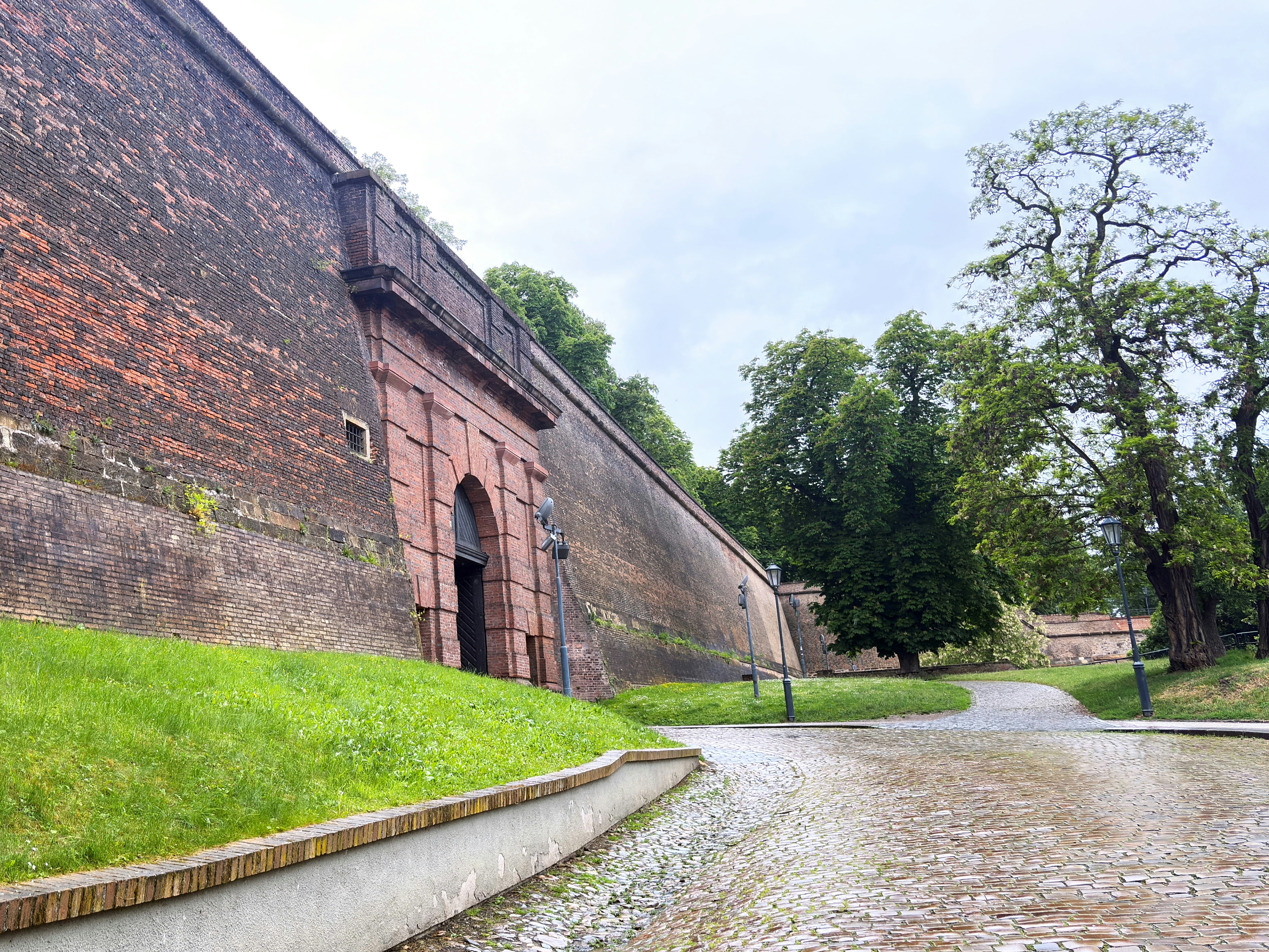 Old brick fortress wall with an arched entrance and trees