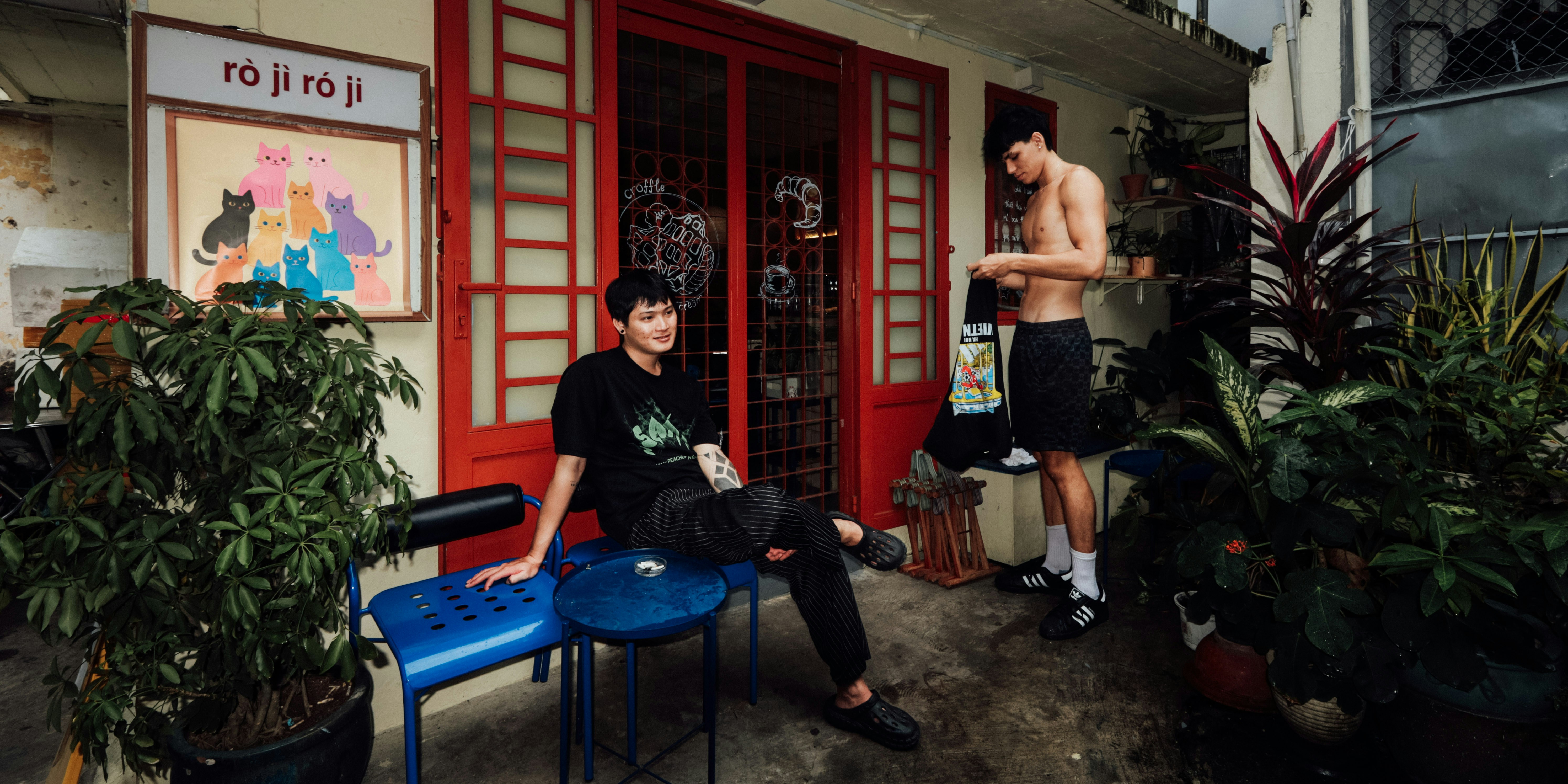 Red storefront retreat: two friends in a sunlit alley café