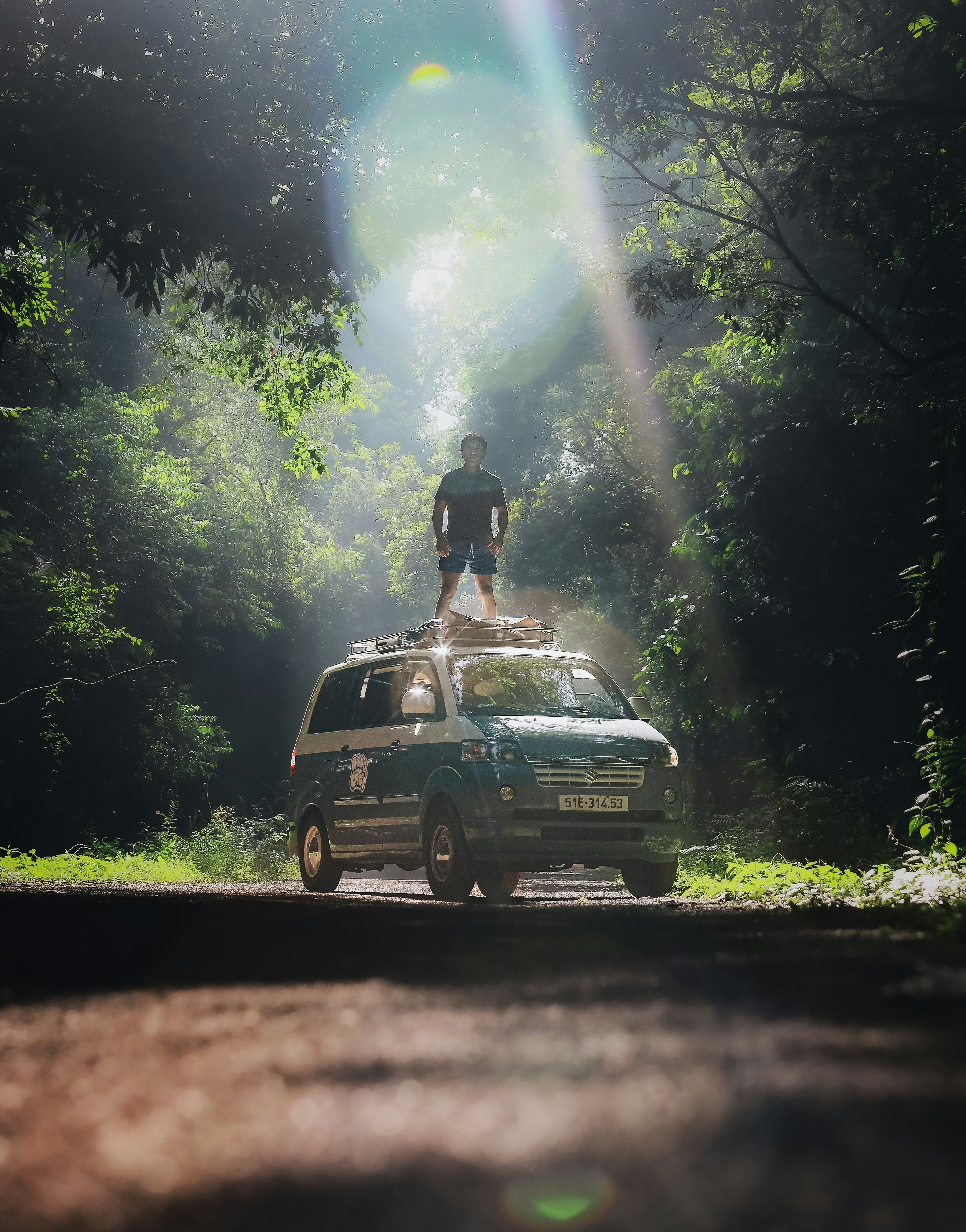 Ridge Rider: A Man on the Roof Amid a Luminous Forest Road