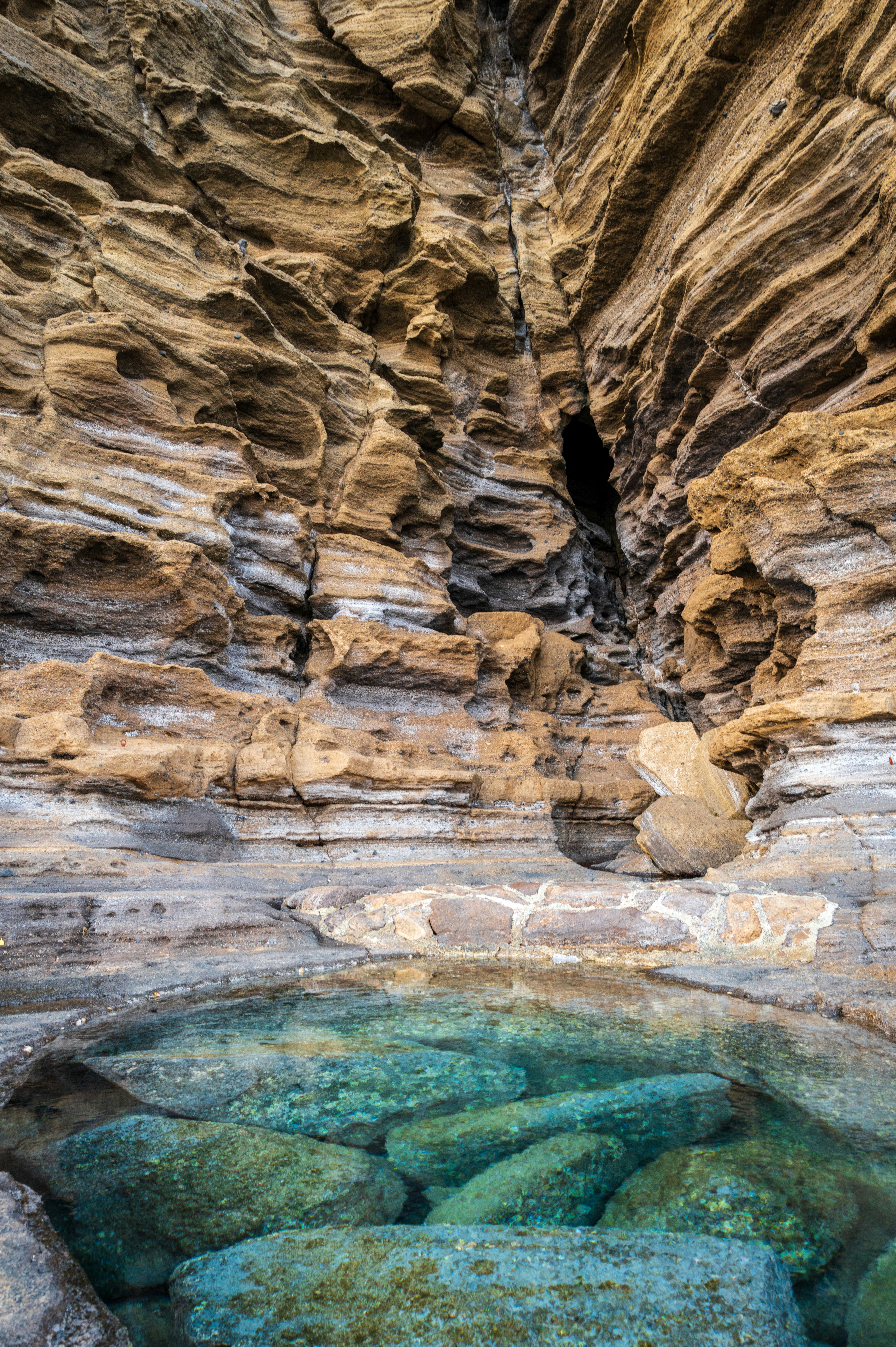 Hidden Tidepool Cavern: Weathered Strata and Clear Green Shallows