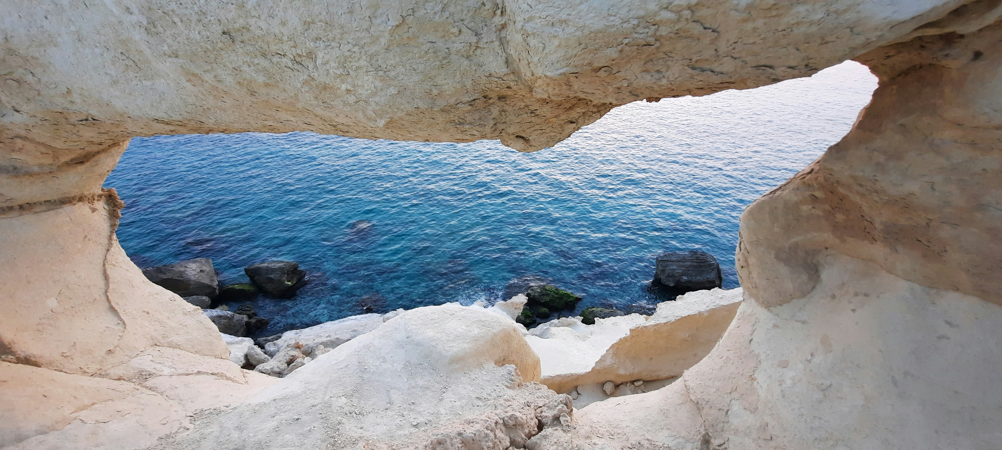 Sea through a cliff window: azure water framed by weathered limestone